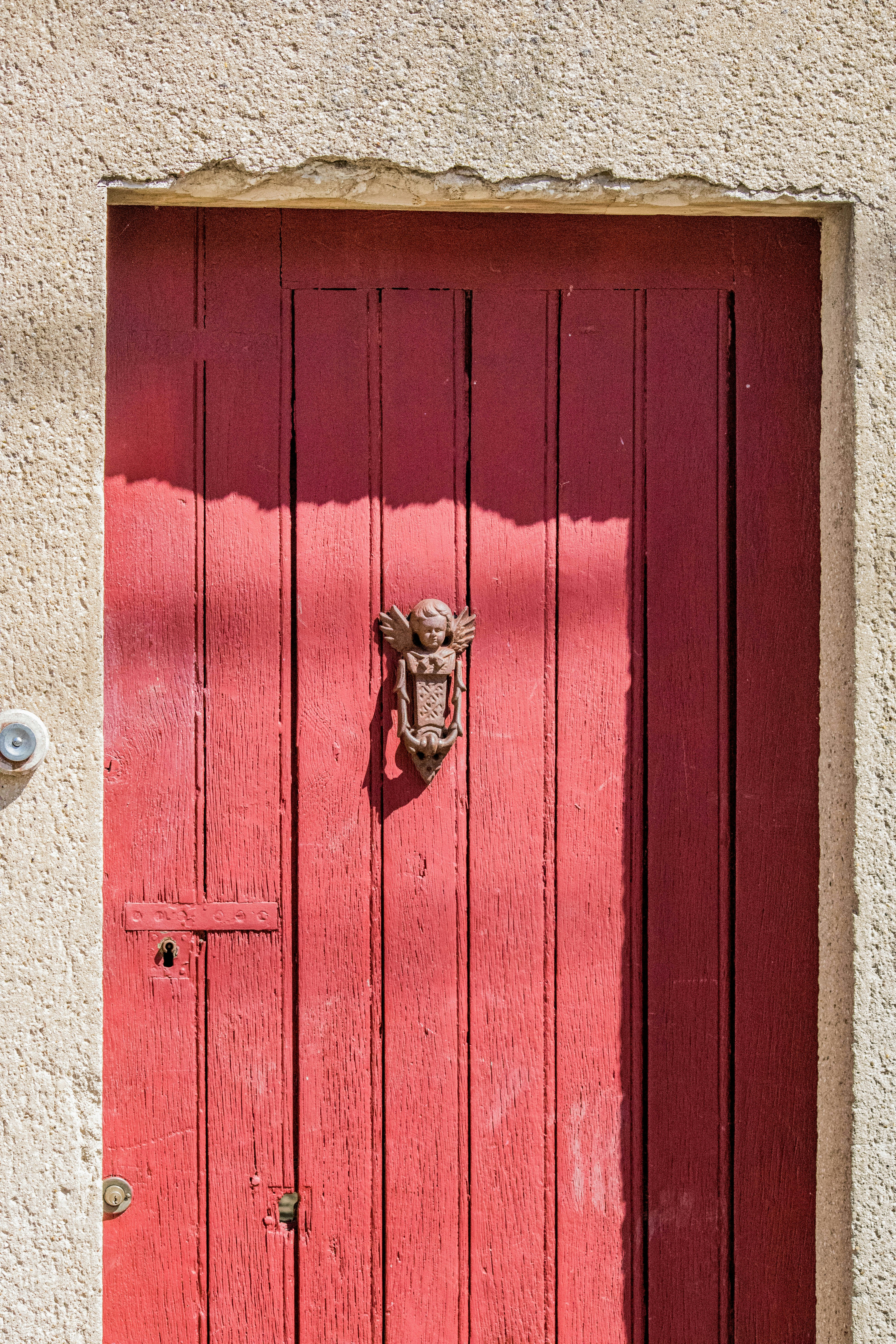 Winged Knocker on a Crimson Door Under Dappled Light