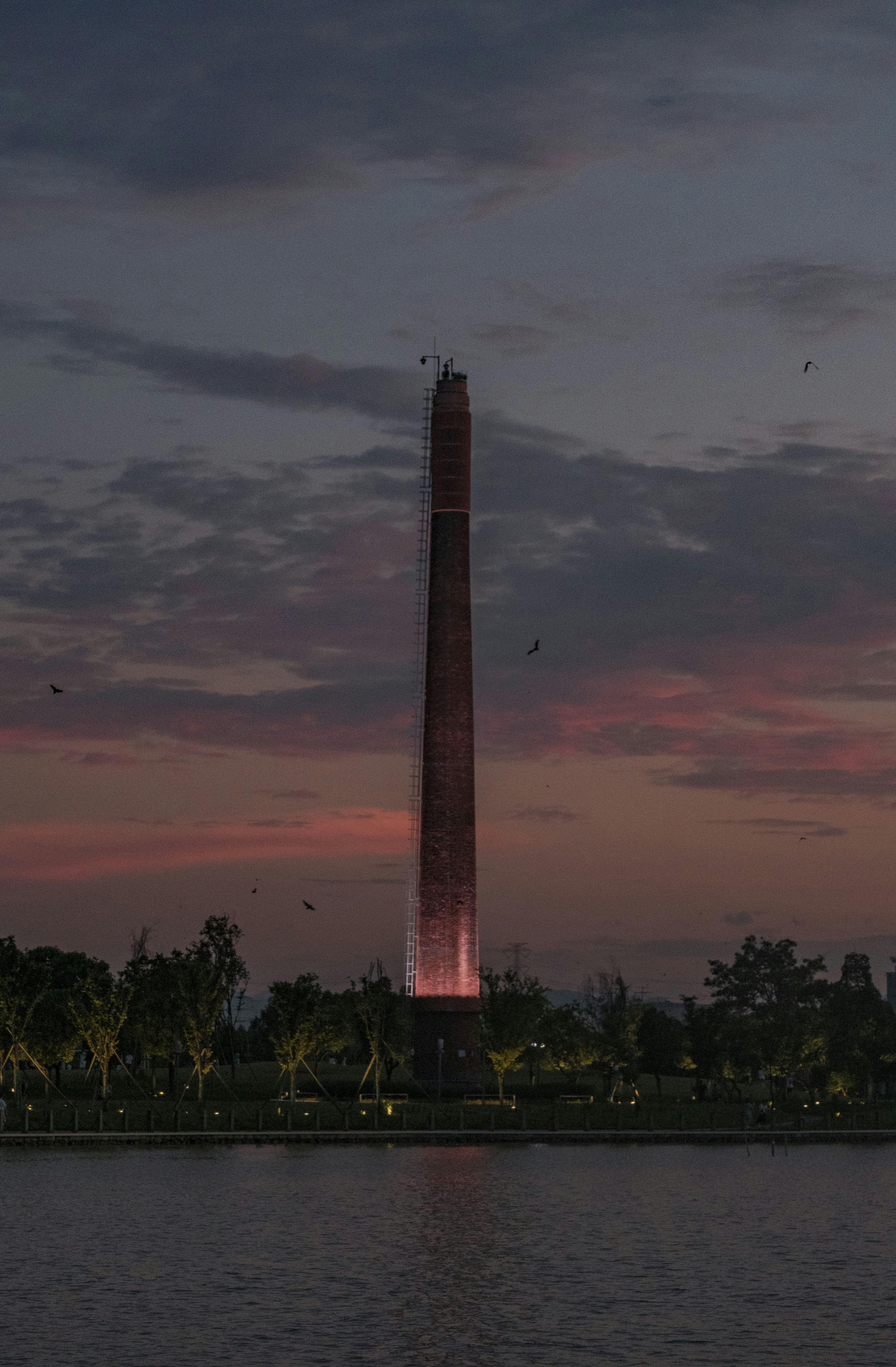 Evening Silhouette: A Lone Smokestack Rises by the Riverside