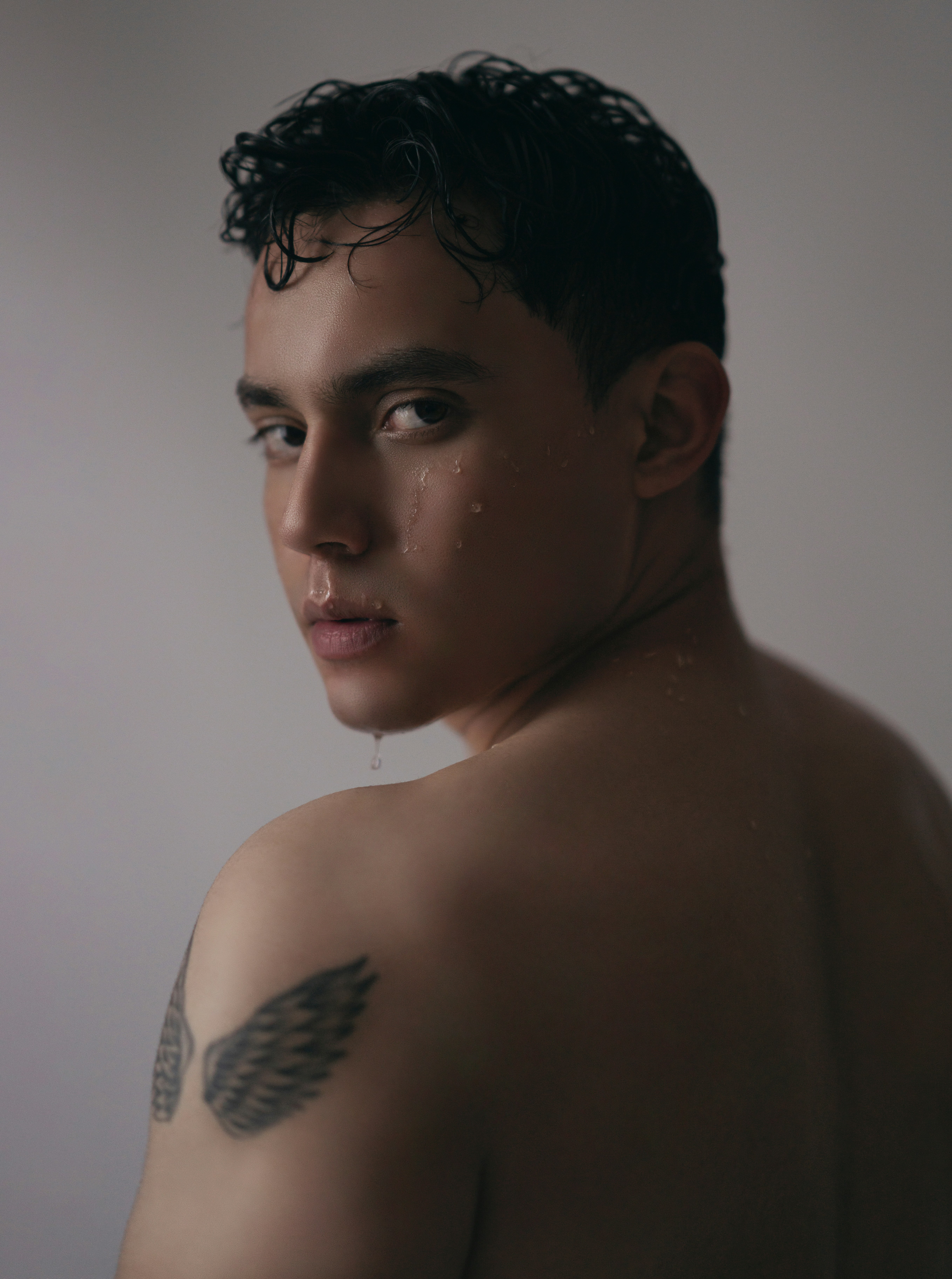 Moist Light, Steady Gaze: Portrait of a Tattooed Shoulder in Soft Shadow
