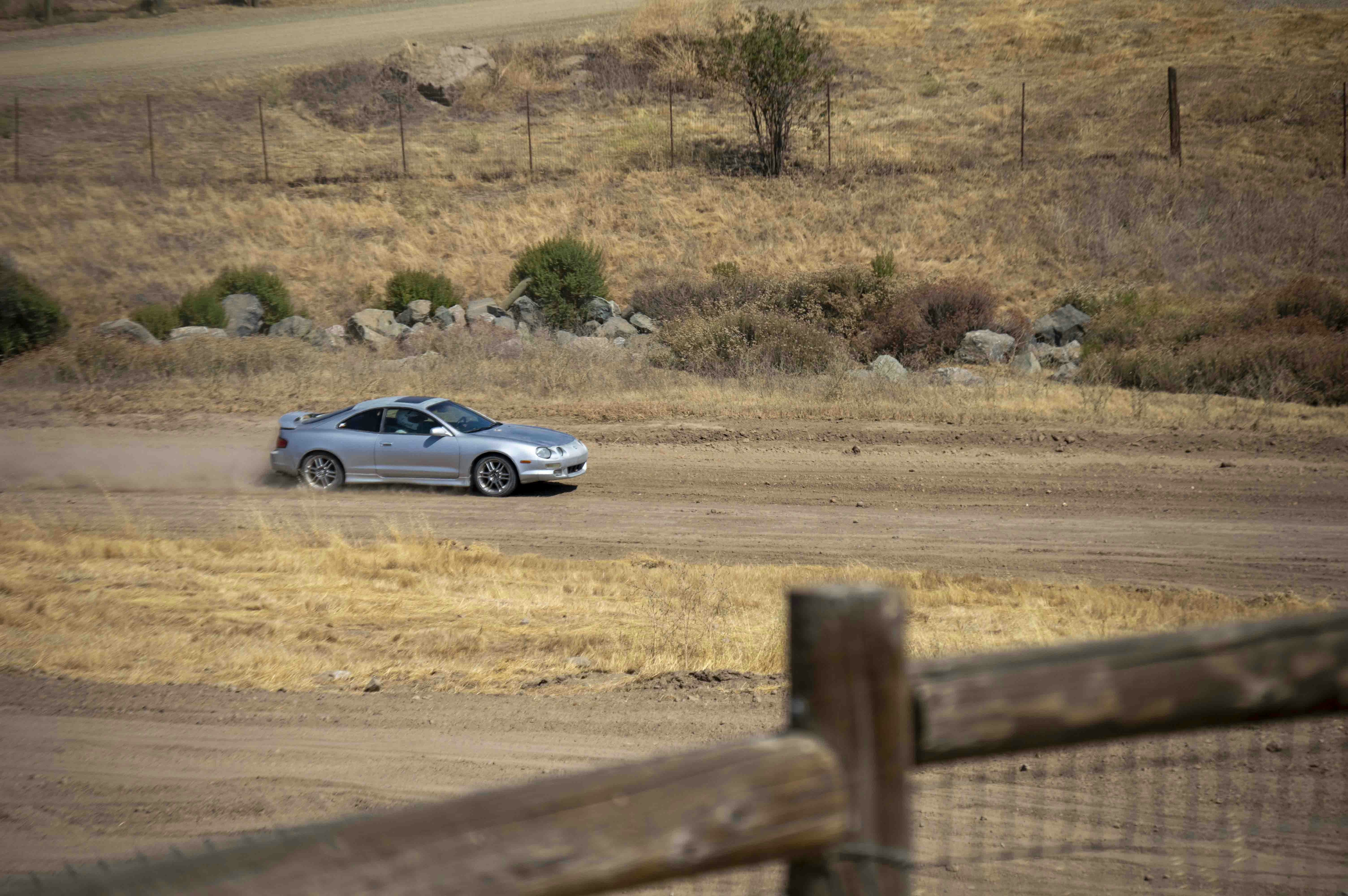 Dust-Swept Sedan Tracing a Quiet Line Along a Rural Dirt Road