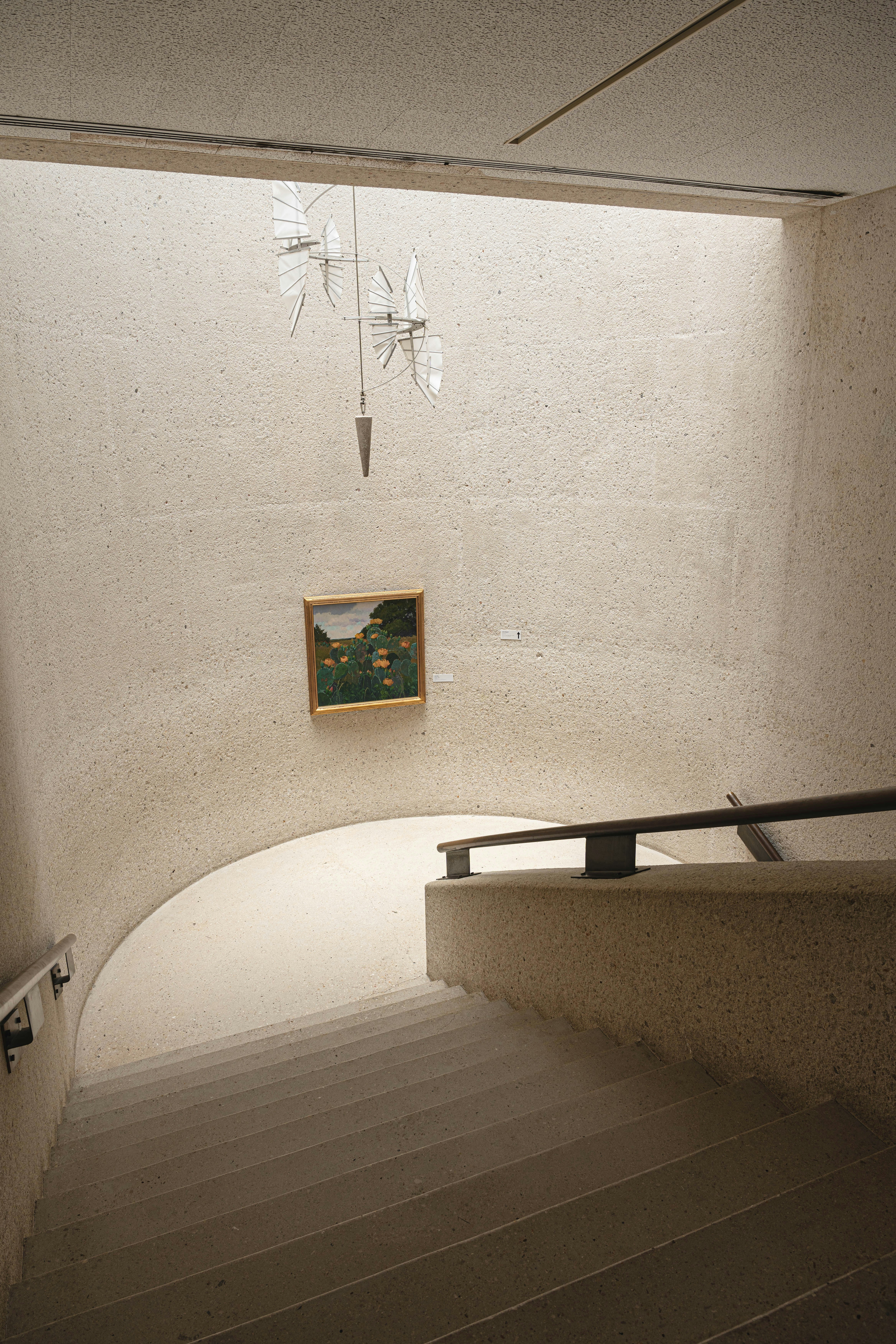 Concrete Stairwell Gallery: Framed Landscape Beneath a Hanging Sculpture