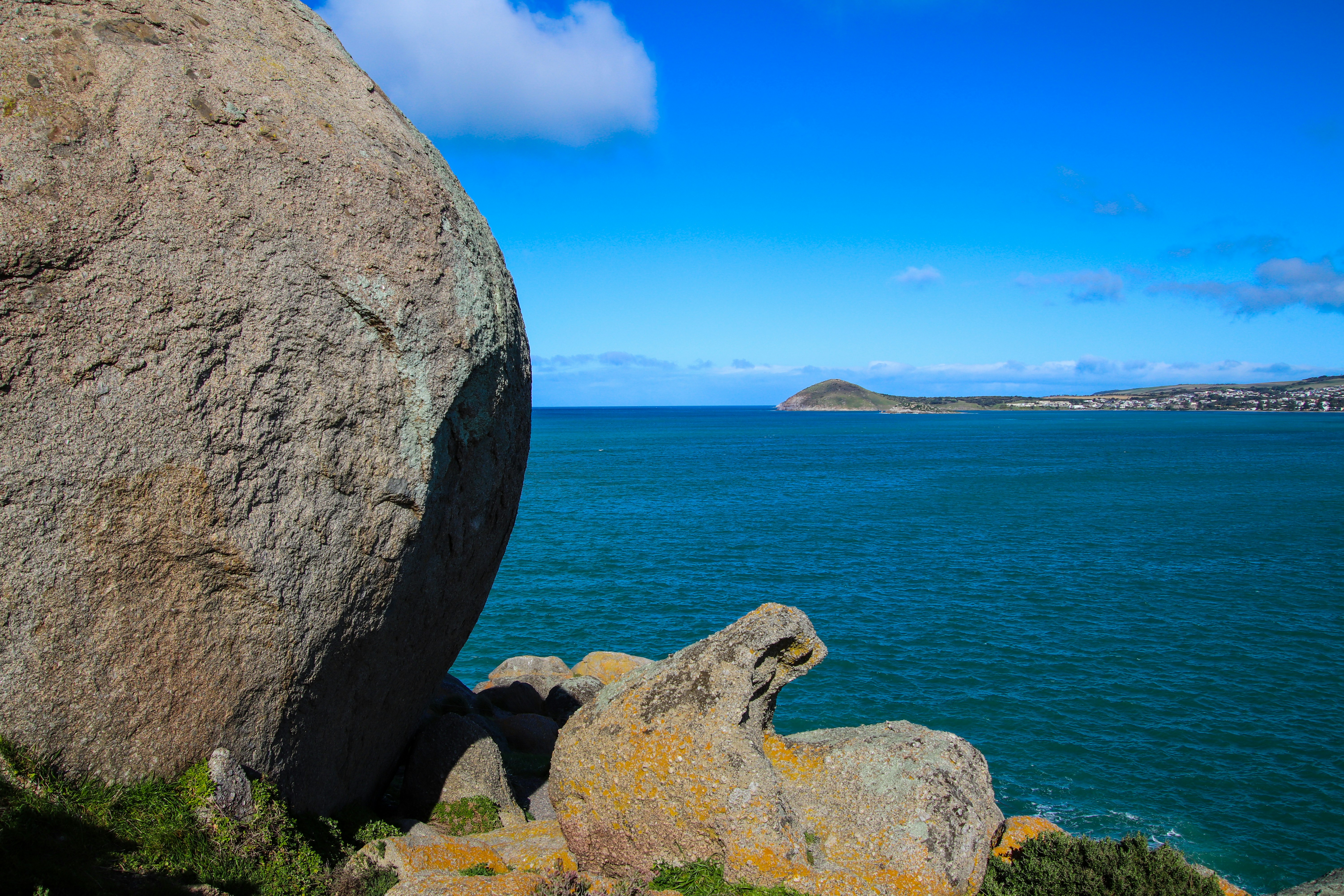 A large rock sitting on top of a lush green hillside photo – Free ...