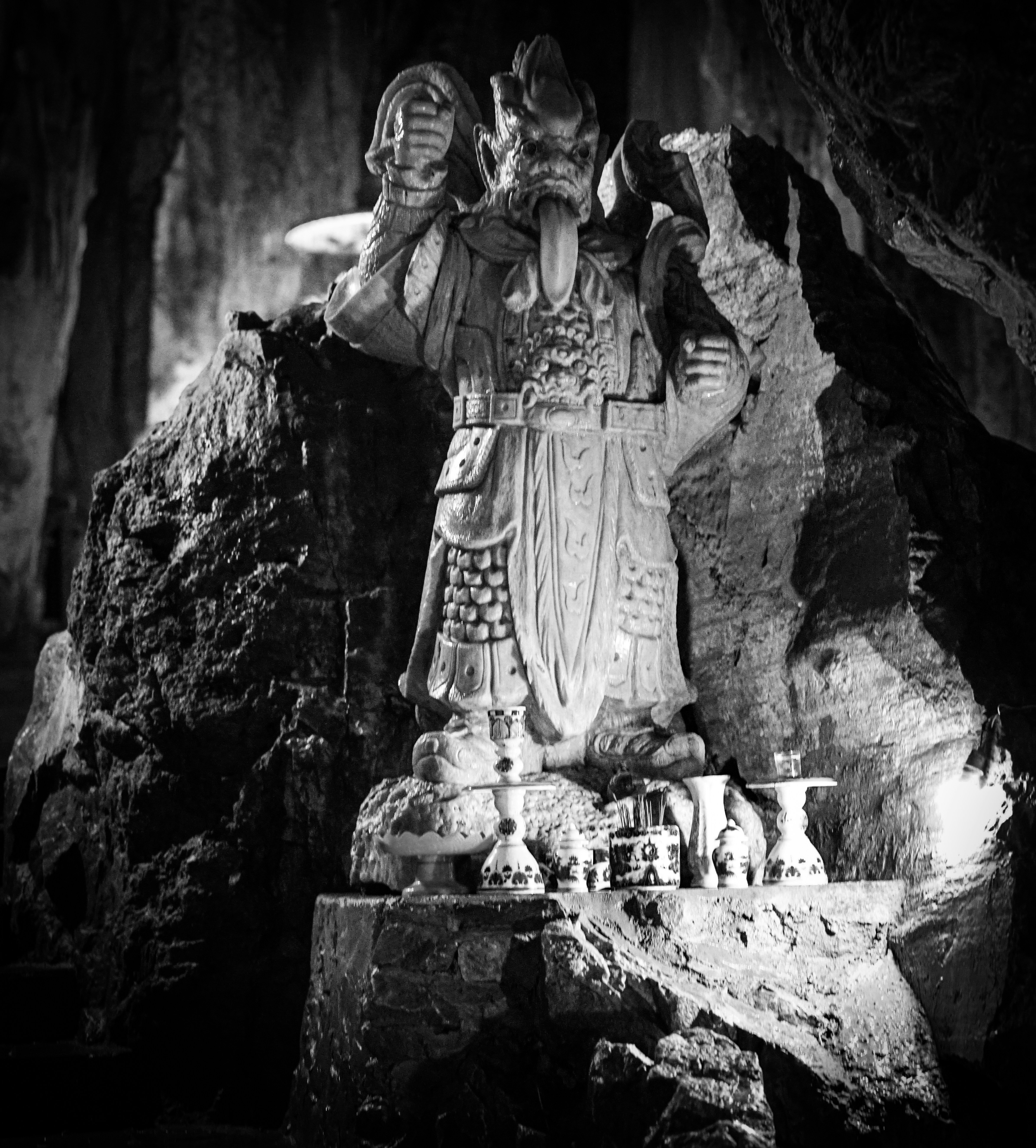 Stone Guardian of the Caves: A Monumental Carved Deity Stands Amid Rough Rock