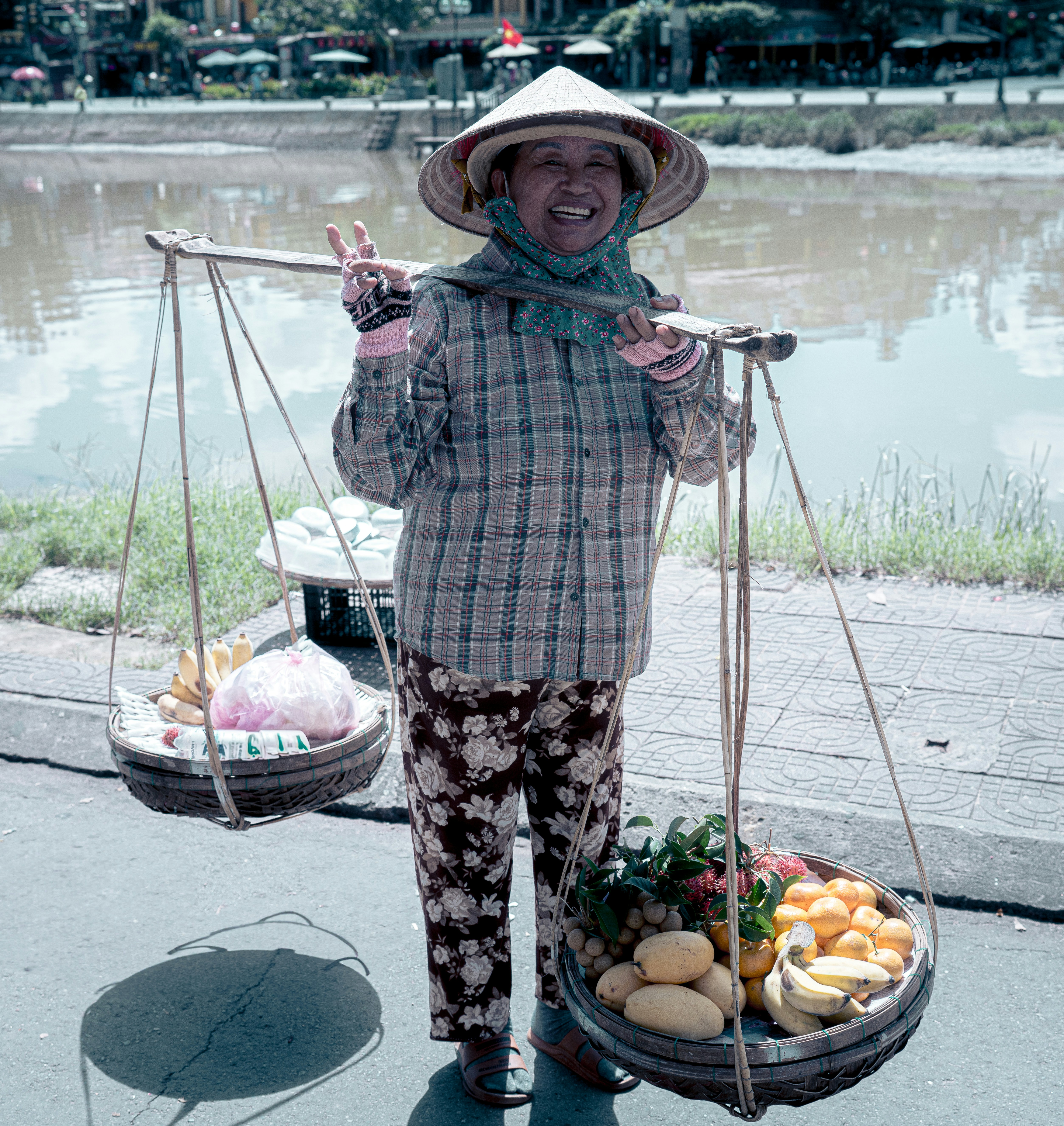 Two-Basket Balance: Riverside Market Vendor in Plaid and Straw Hat