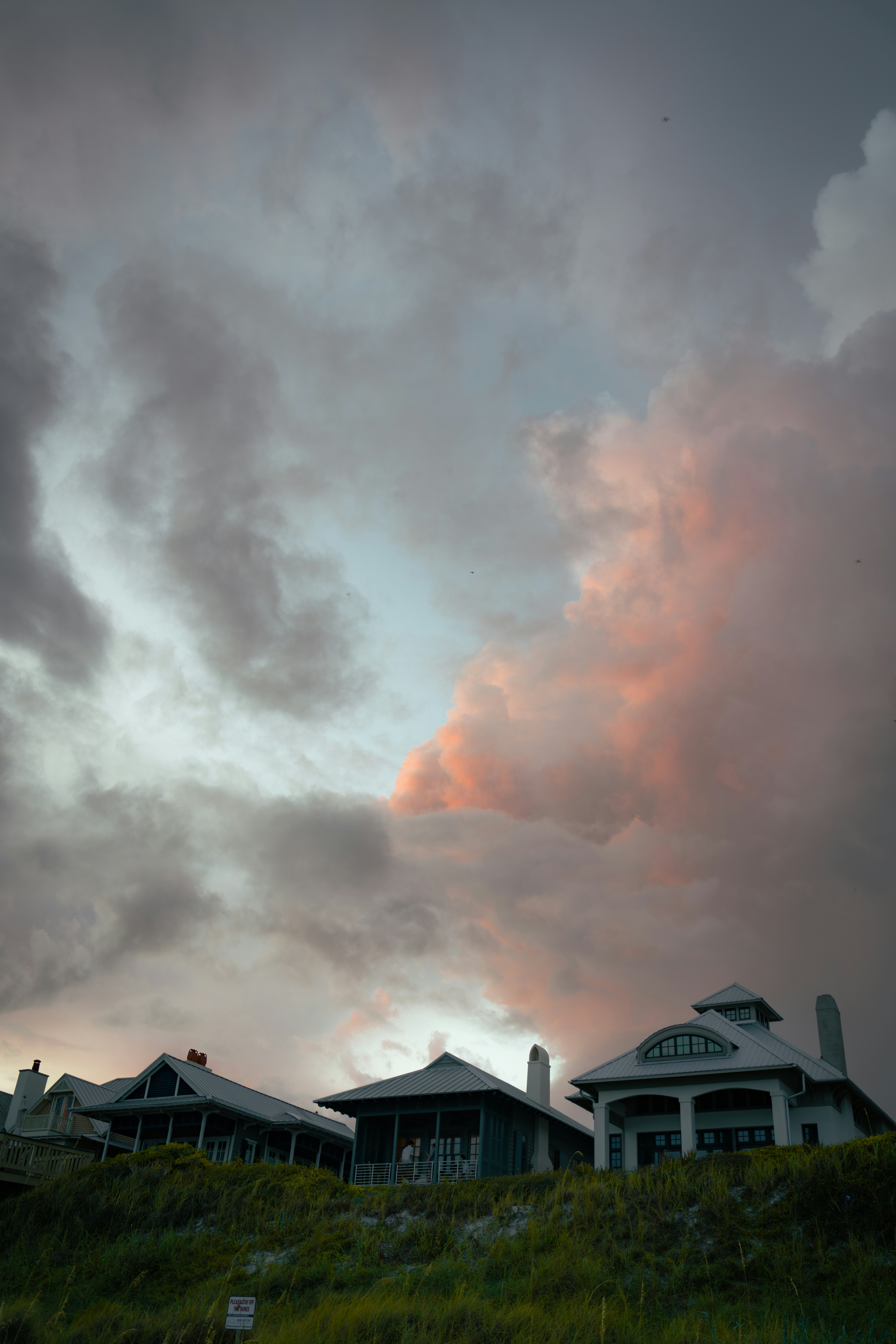 Dune Row at Dusk: Coral Clouds Over a Quiet Coastal Village