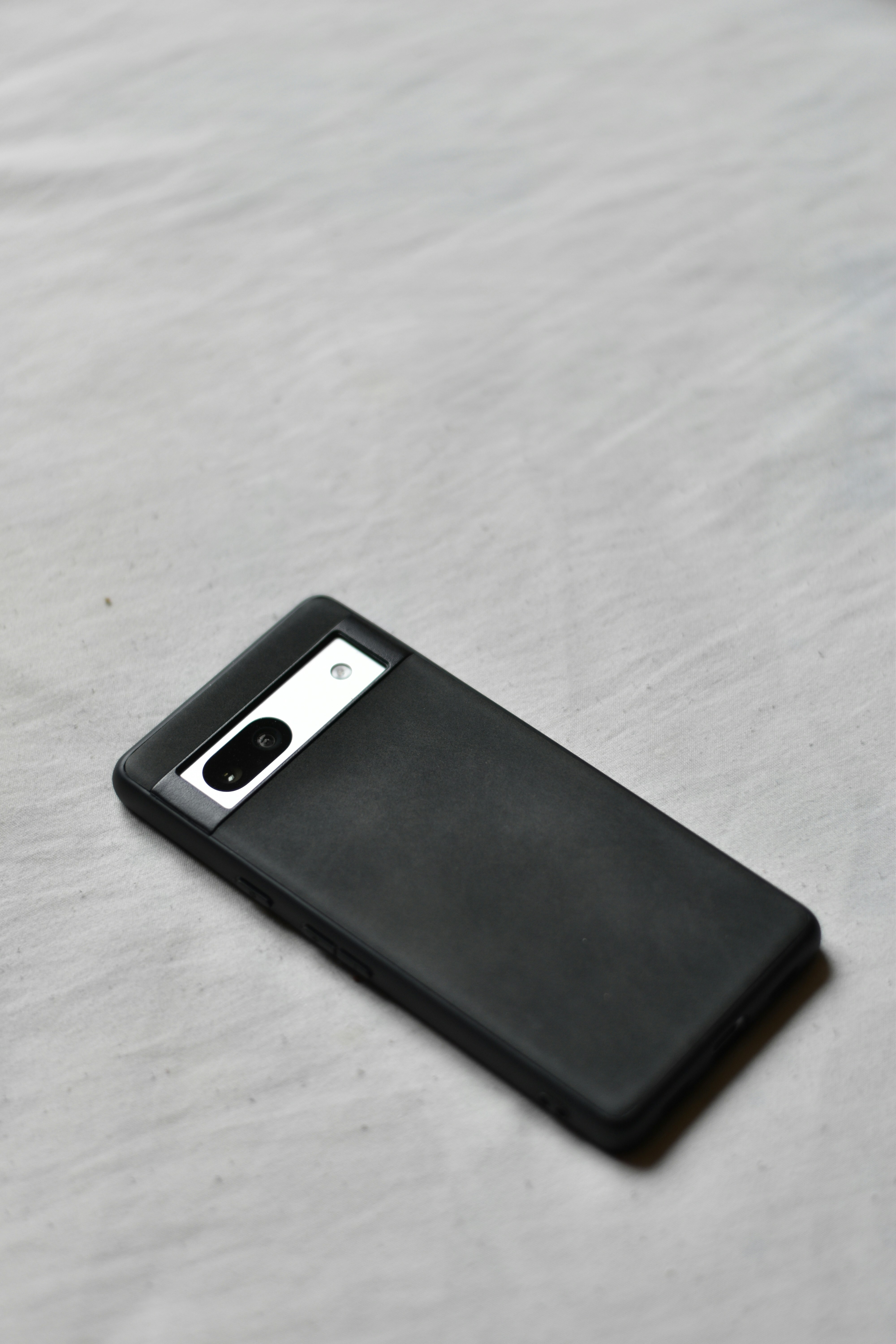 Black smartphone resting on a light-colored surface, showcasing its sleek design and modern aesthetics.