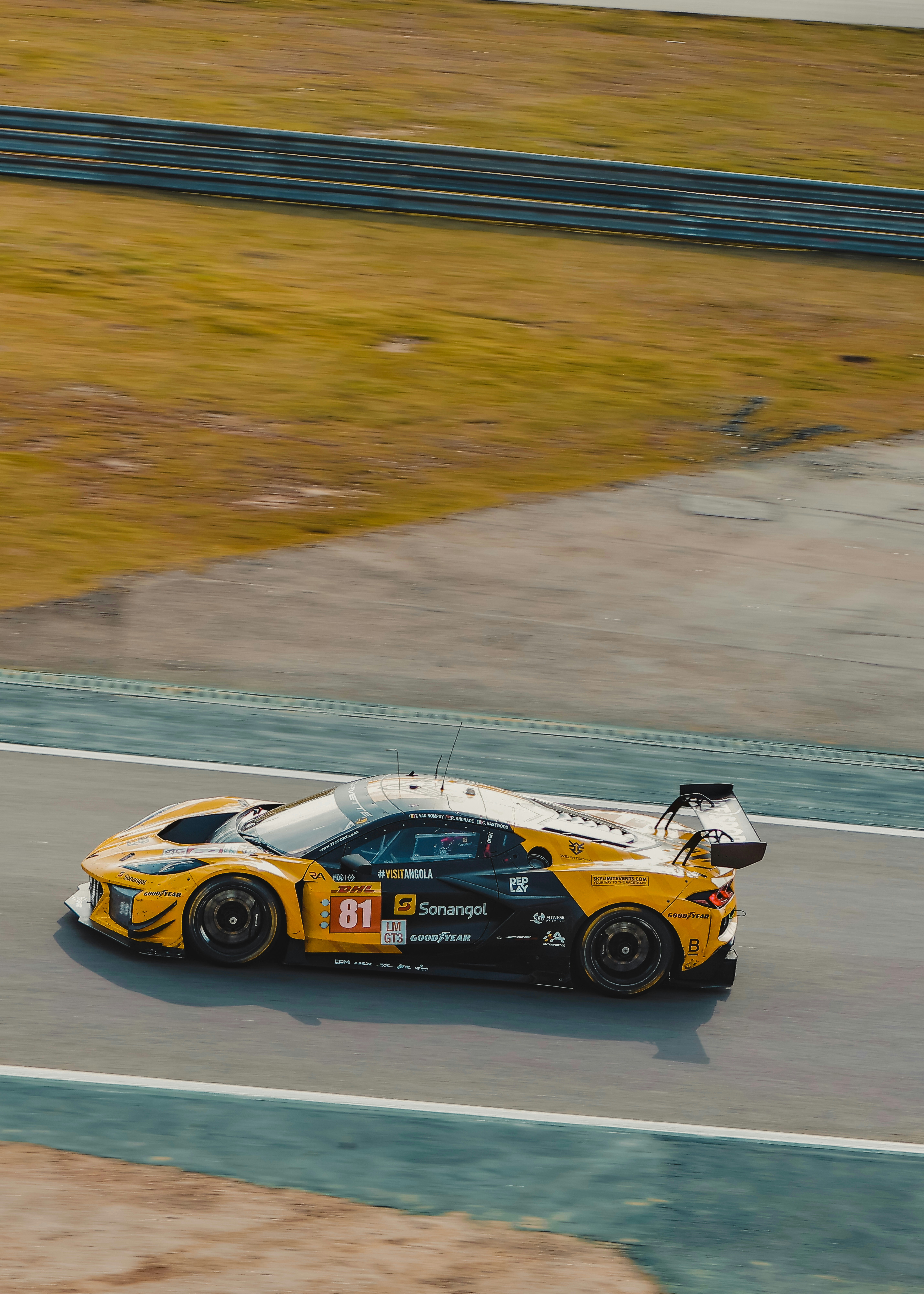 A yellow race car driving down a race track photo – Free Automobile ...