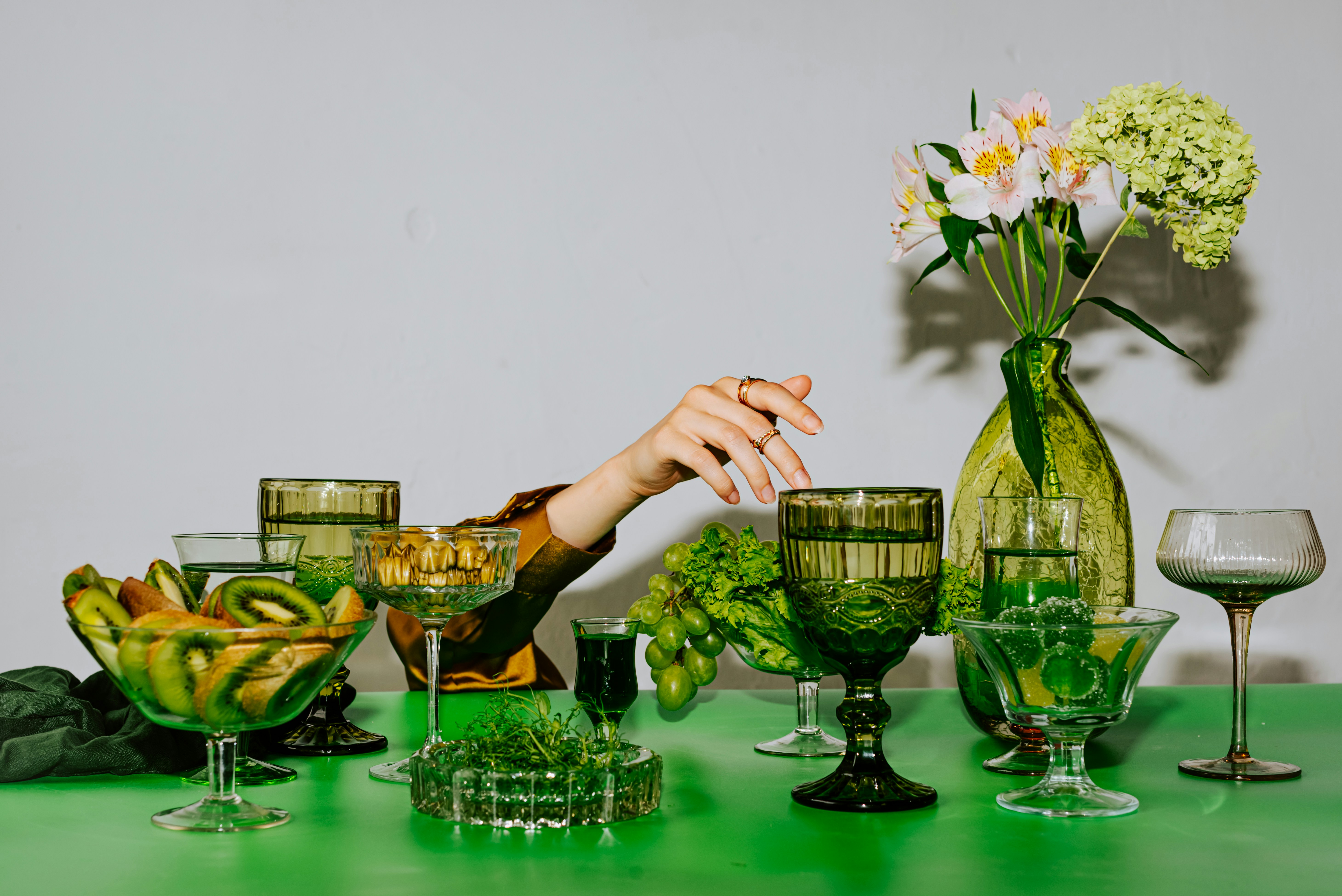 Green Glass, Gold Rim, and a Hand in Motion at a Tablescape