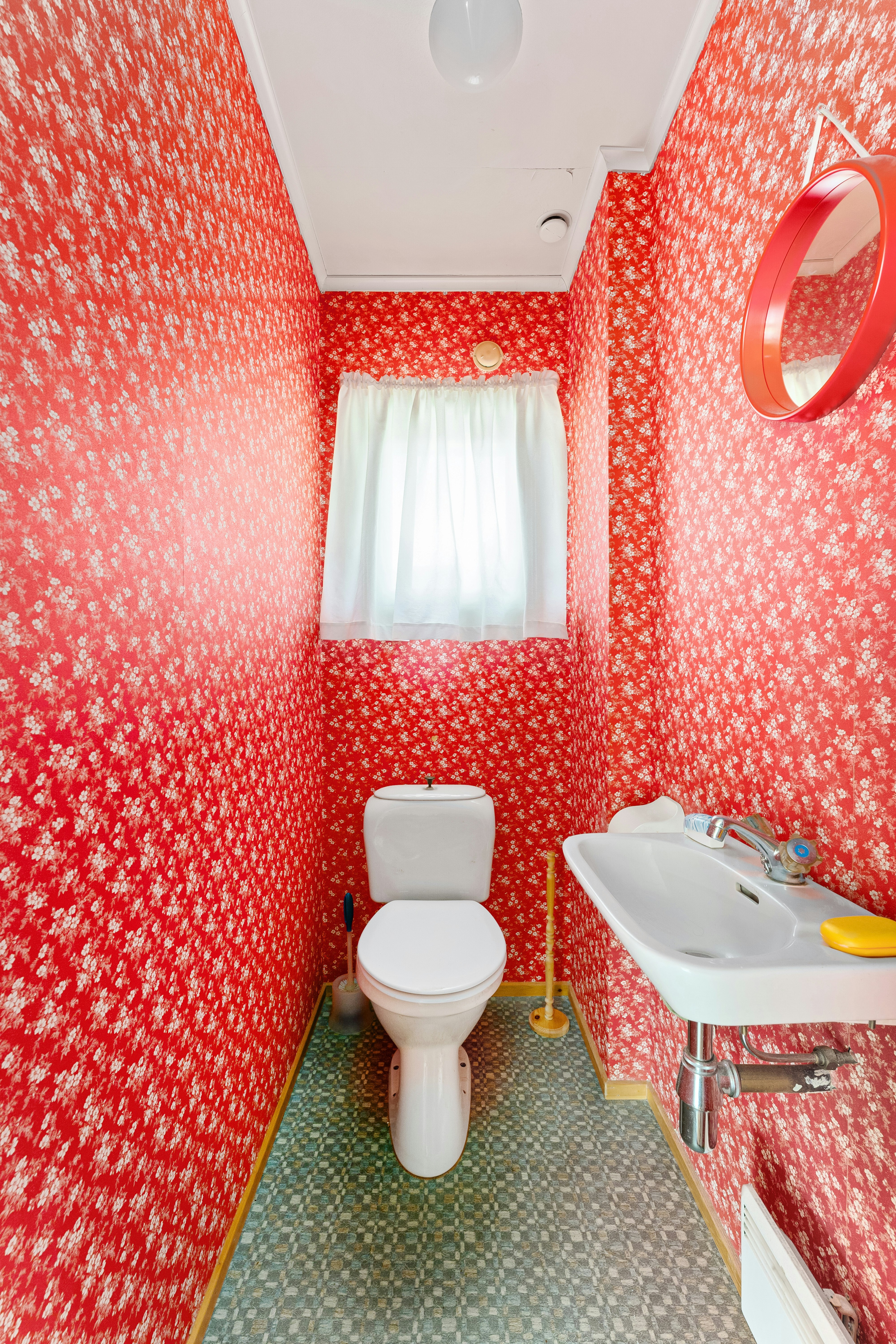 Crimson Corridors: A Tiny Bathroom Framed by Floral Walls and White Fixtures