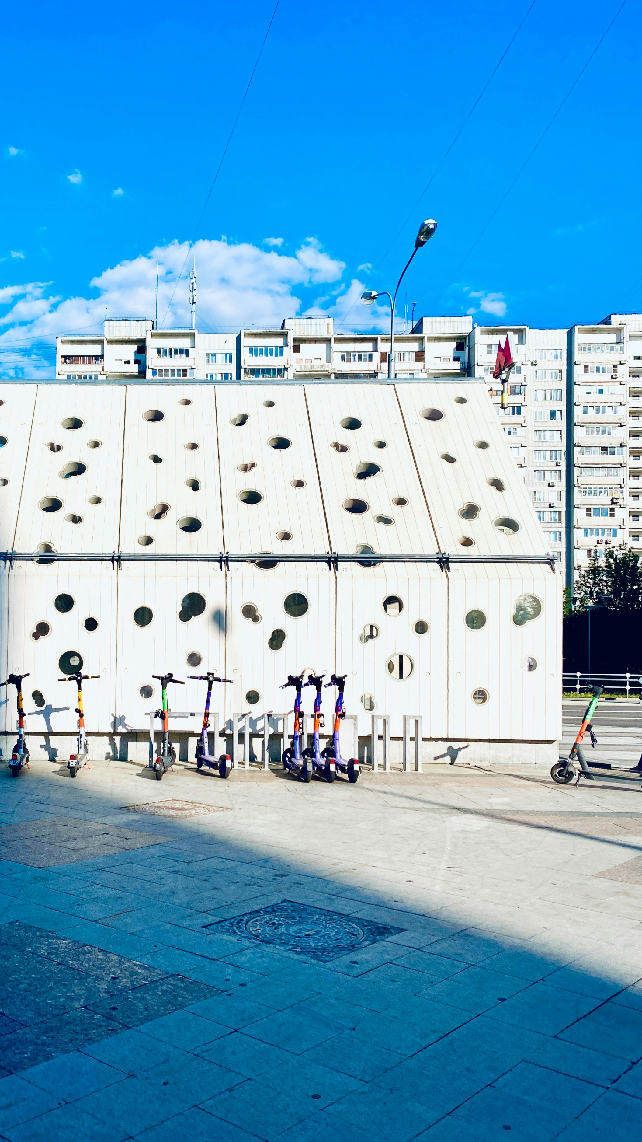 The Orbed Wall: A Dotted Concrete Landmark Framing Electric Scooters