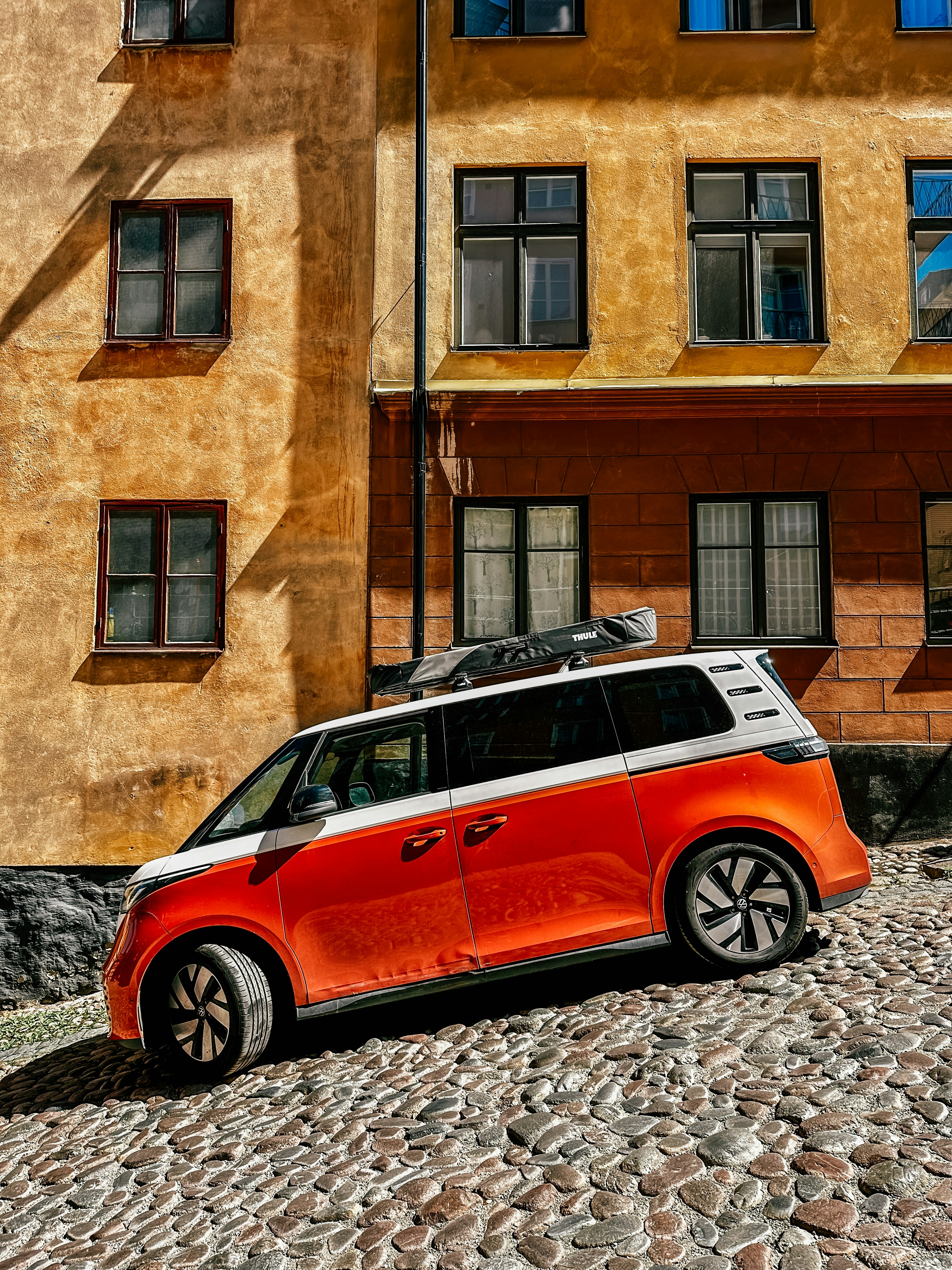 Orange Microbus on Cobblestones Before a Amber Facade