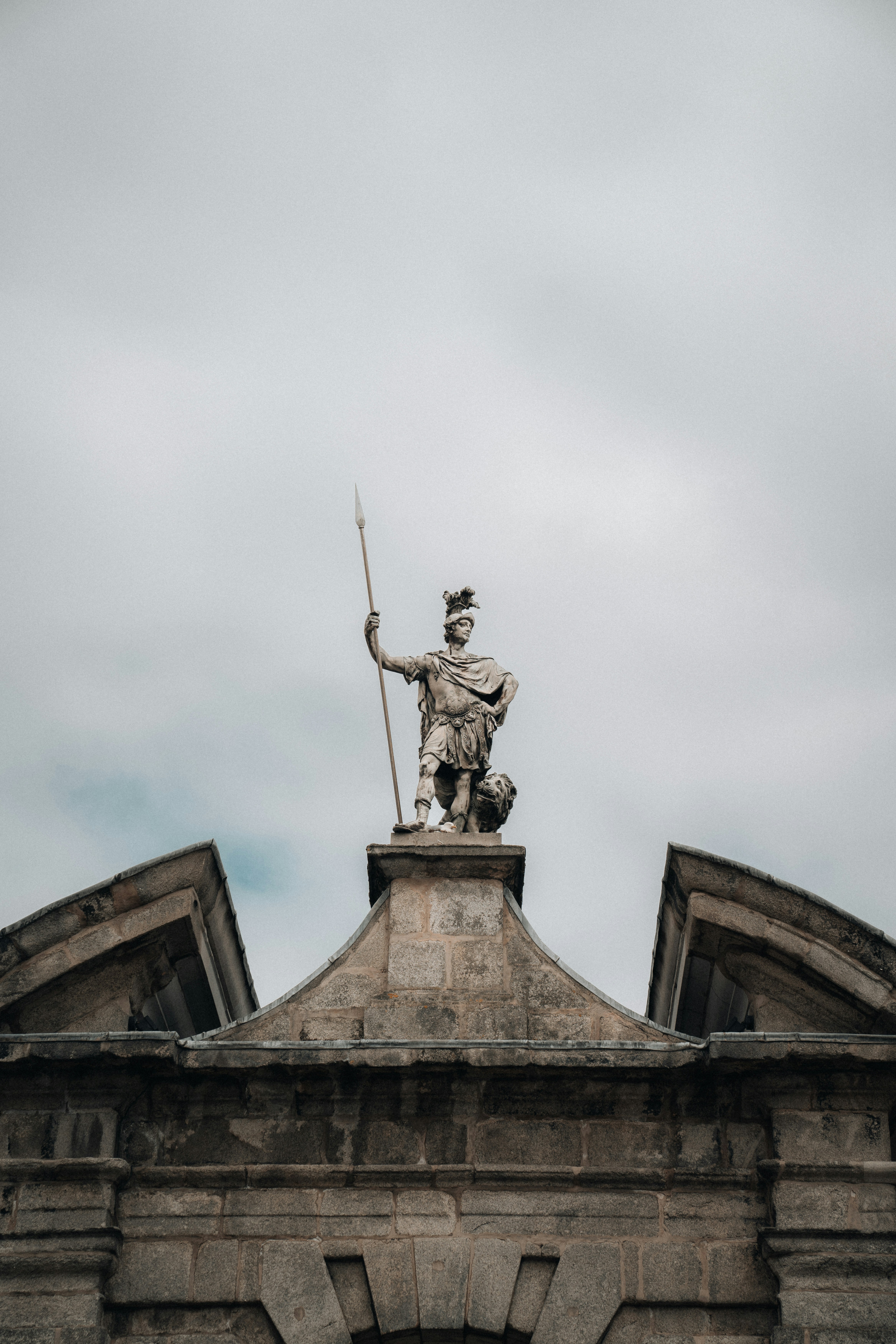 Sentinel on Stone: A Classical Statue Crowns the Weathered Facade
