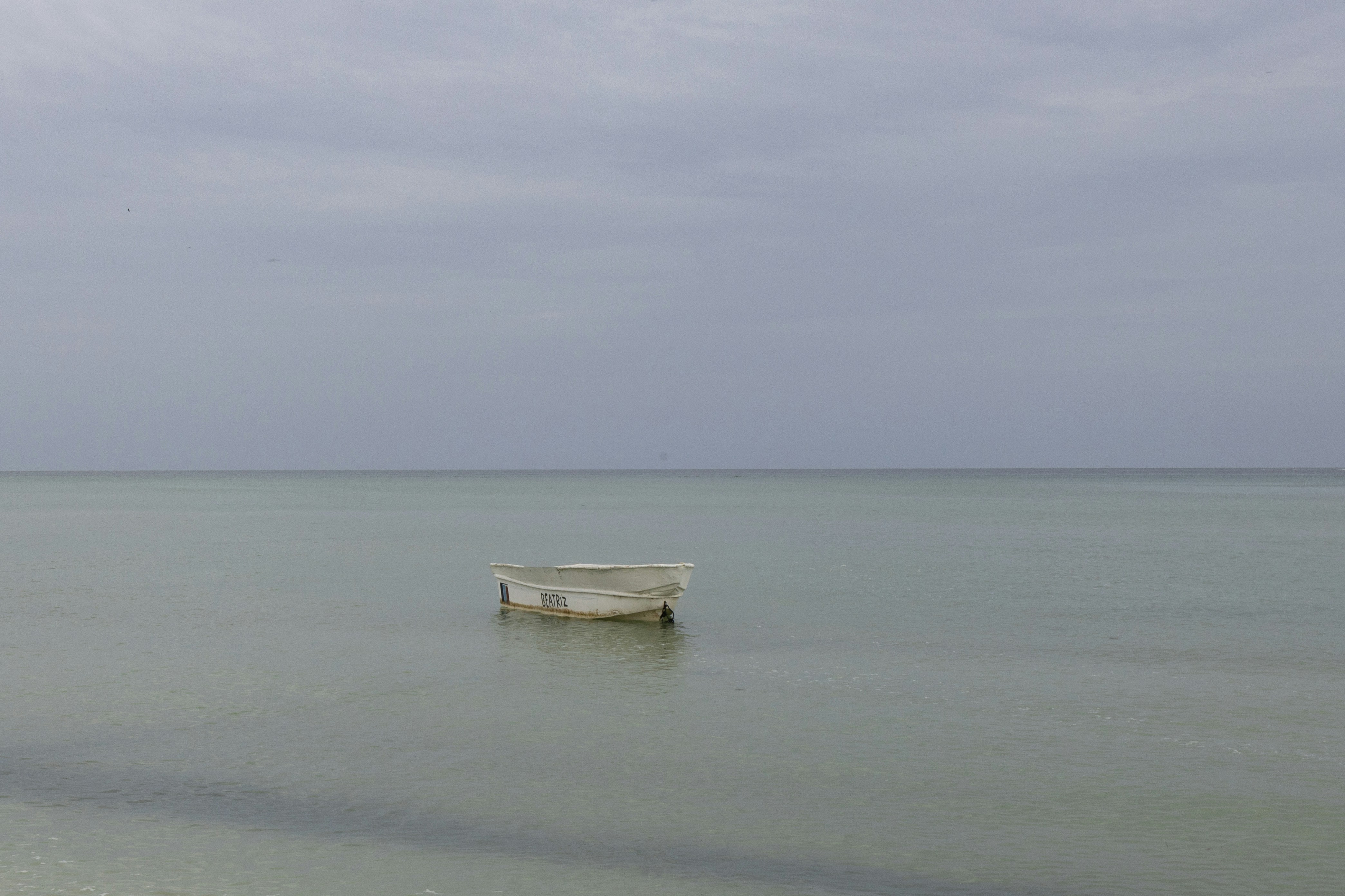 Lone Vessel on a Glassy Pale Sea Beneath Quiet Skies