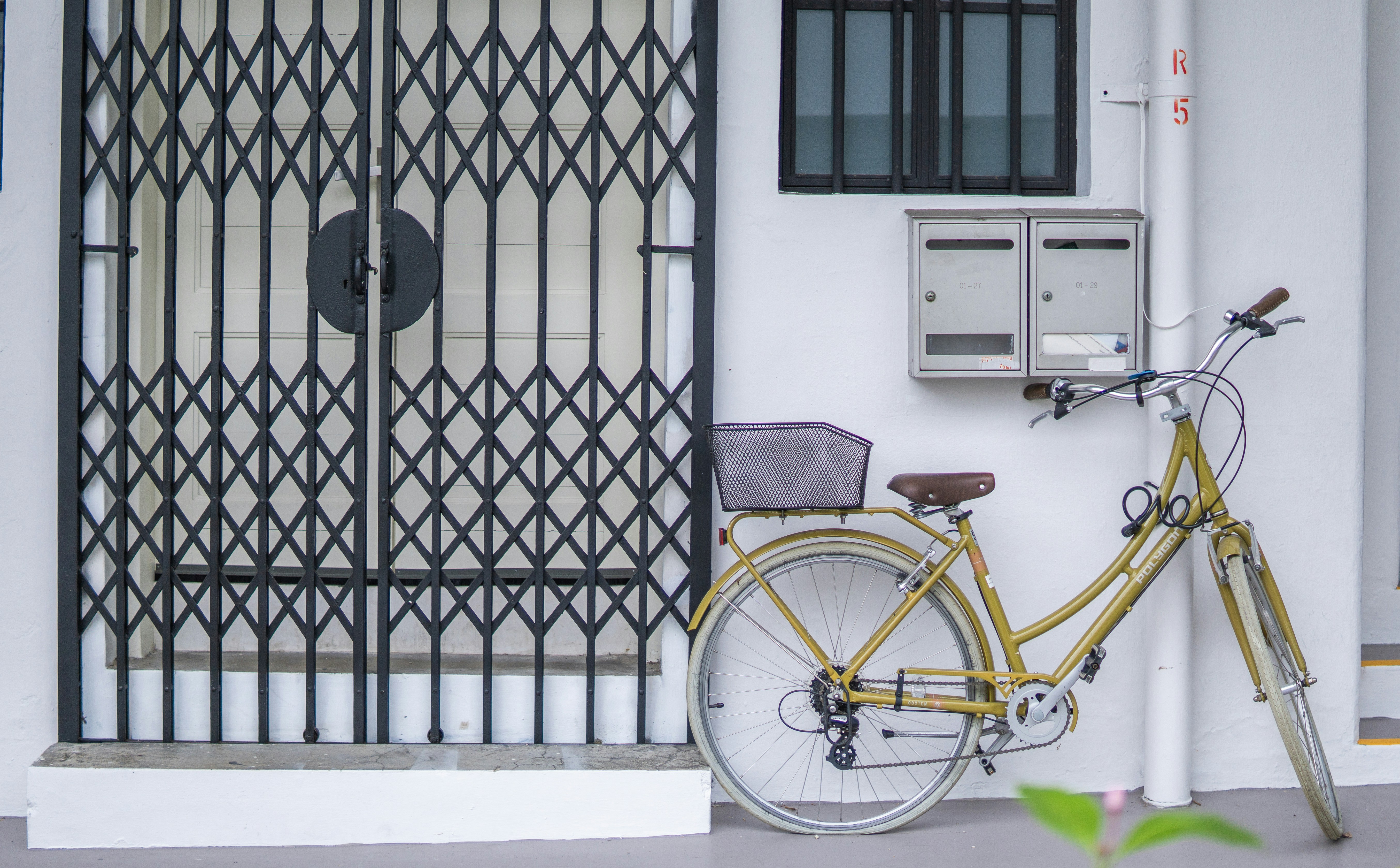 A bicycle parked in front of a building with a gate photo – Free ...