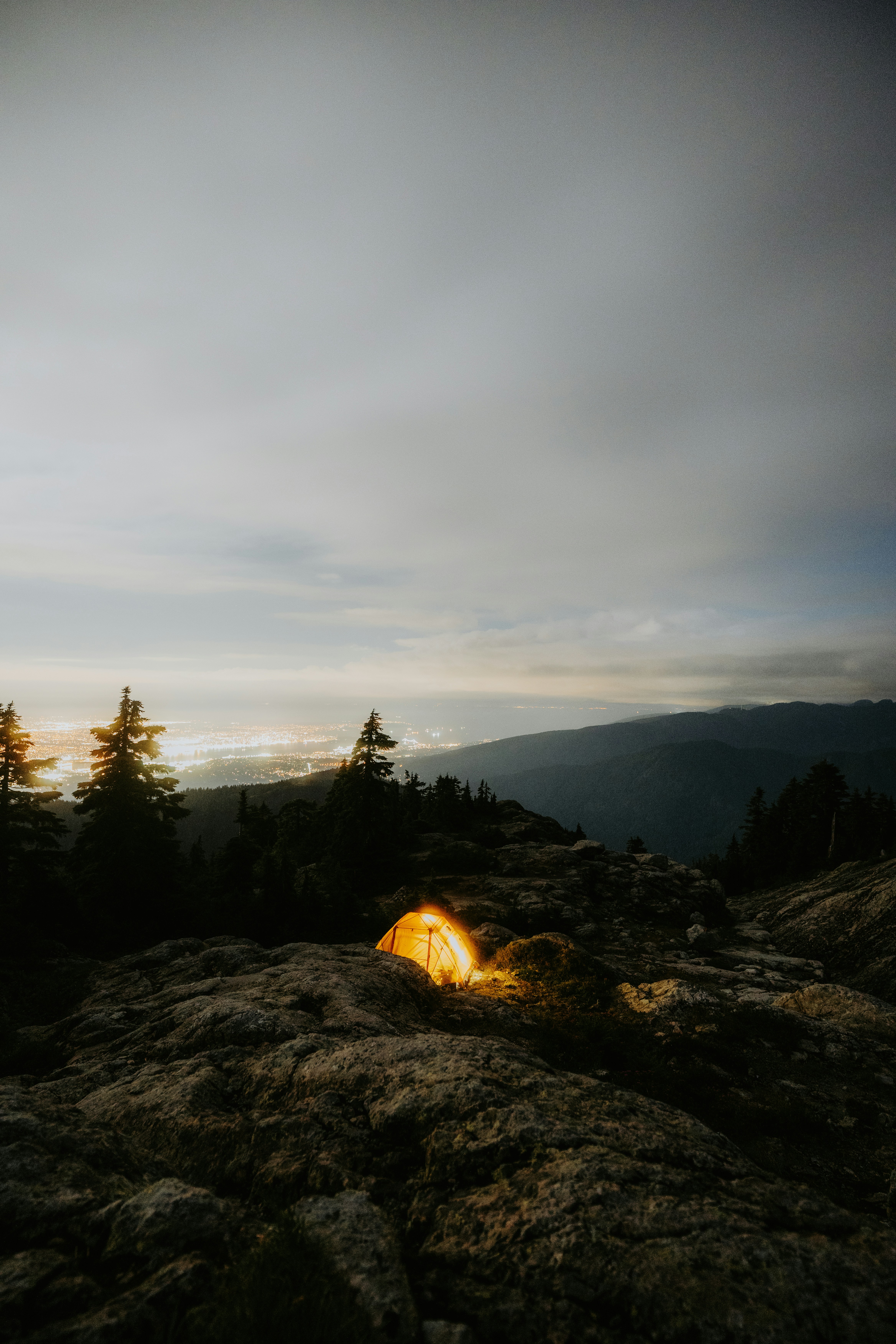Glow in the Crags: A Lone Tent Beneath the Distant Skies
