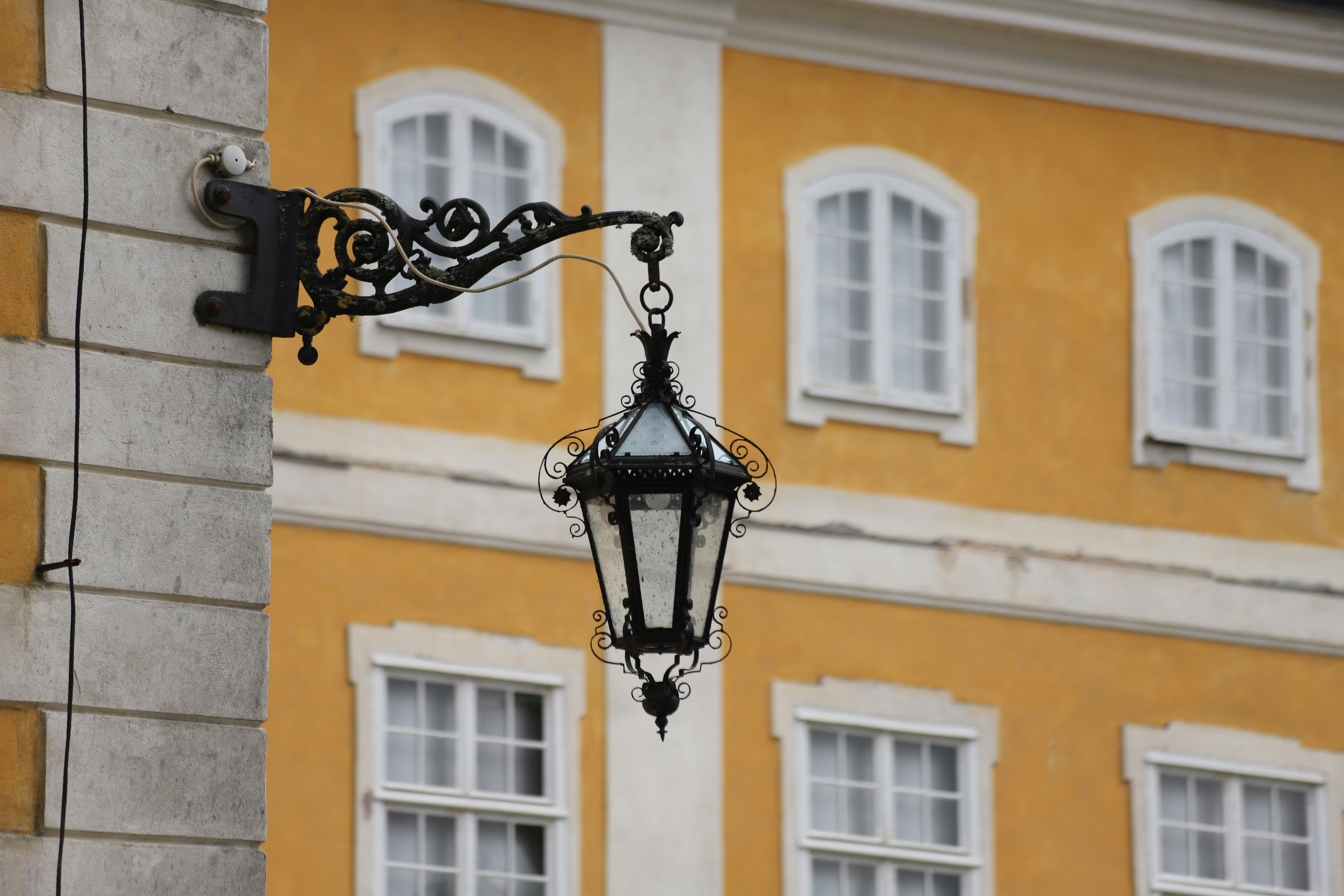 Wrought-Iron Lantern Framed by a Sunlit Yellow Facade