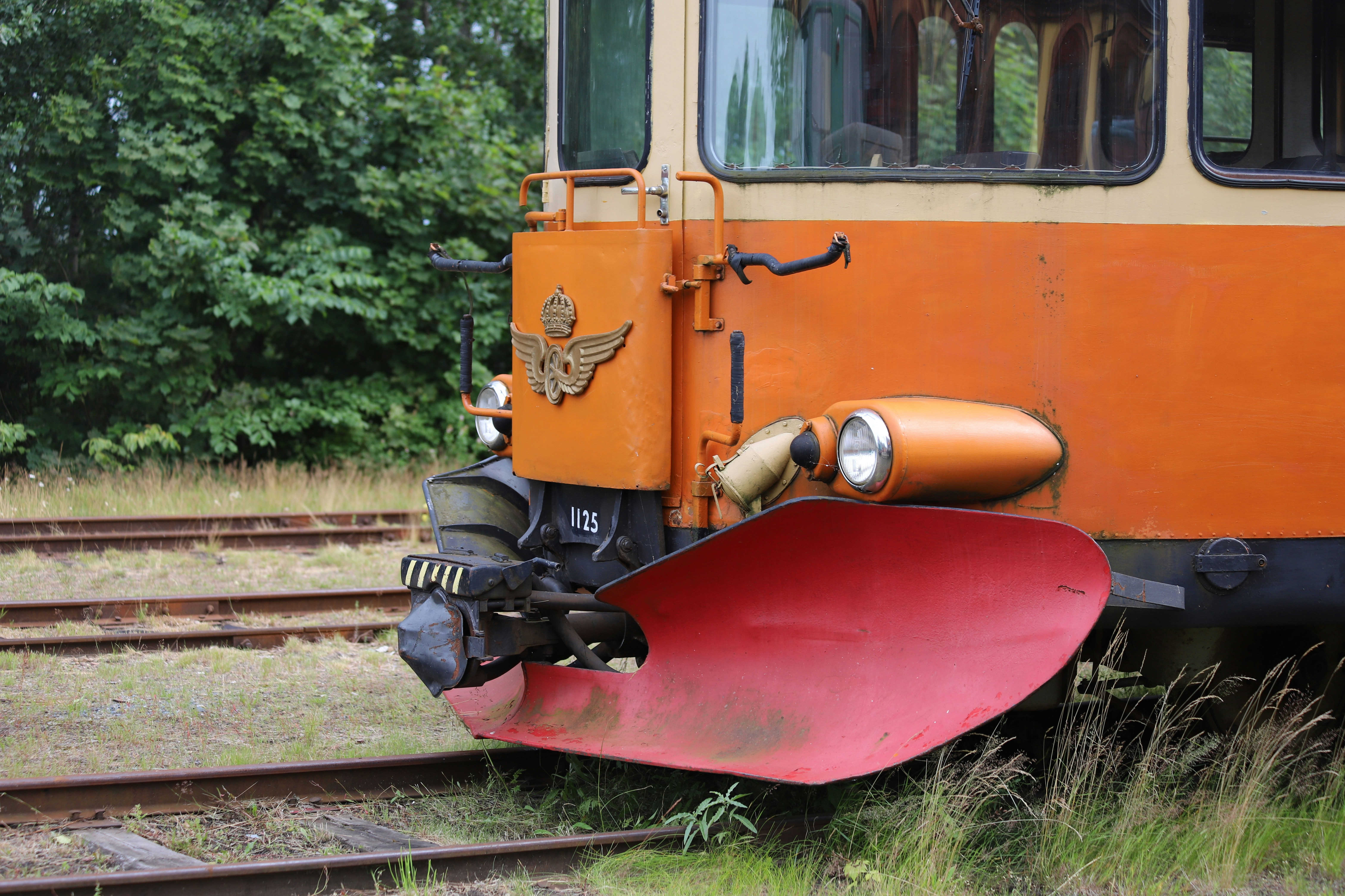 Bold Front of a Vintage Orange Railcar with a Red Snow Plow