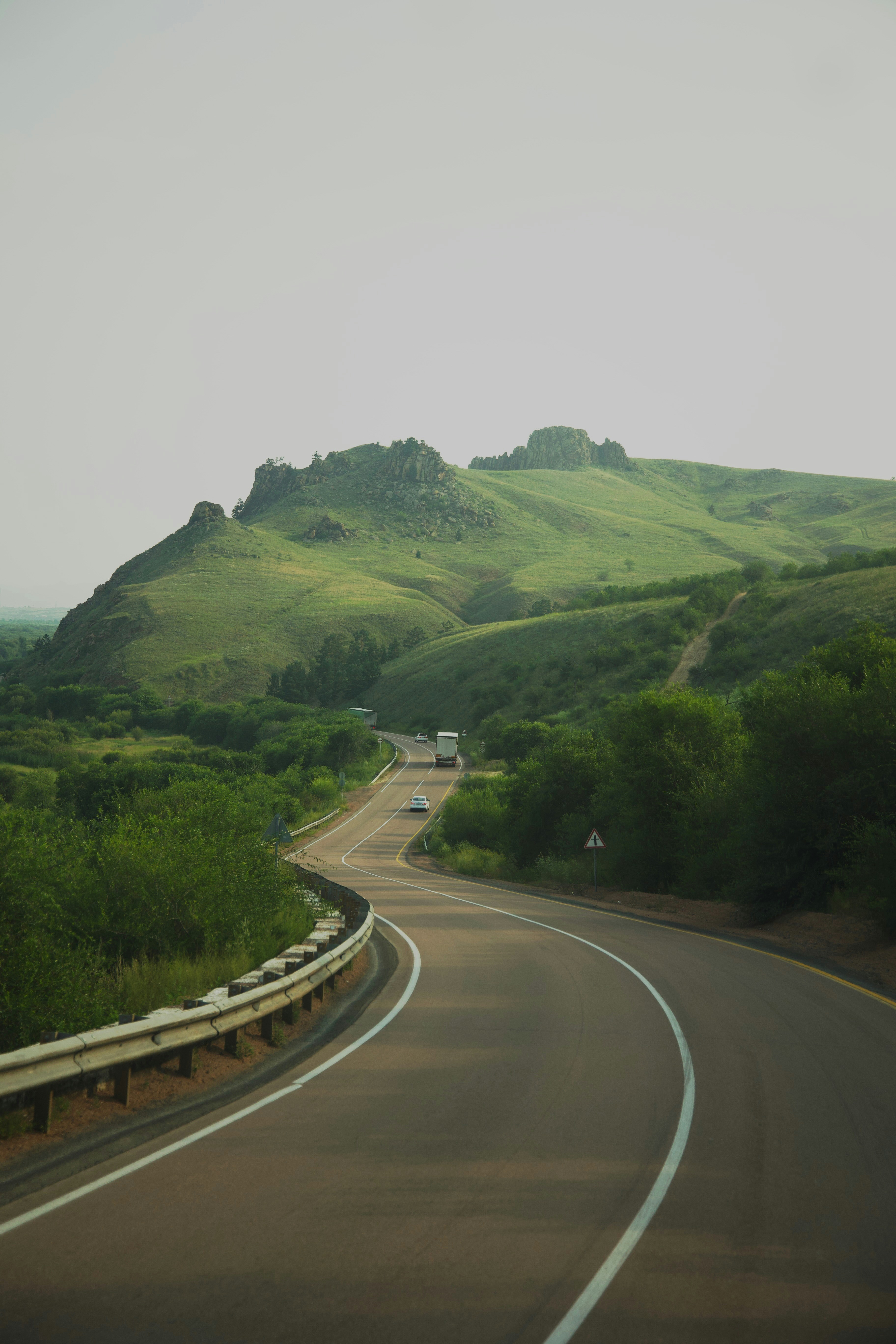 A curved road with a hill in the background photo – Free Road Image on ...