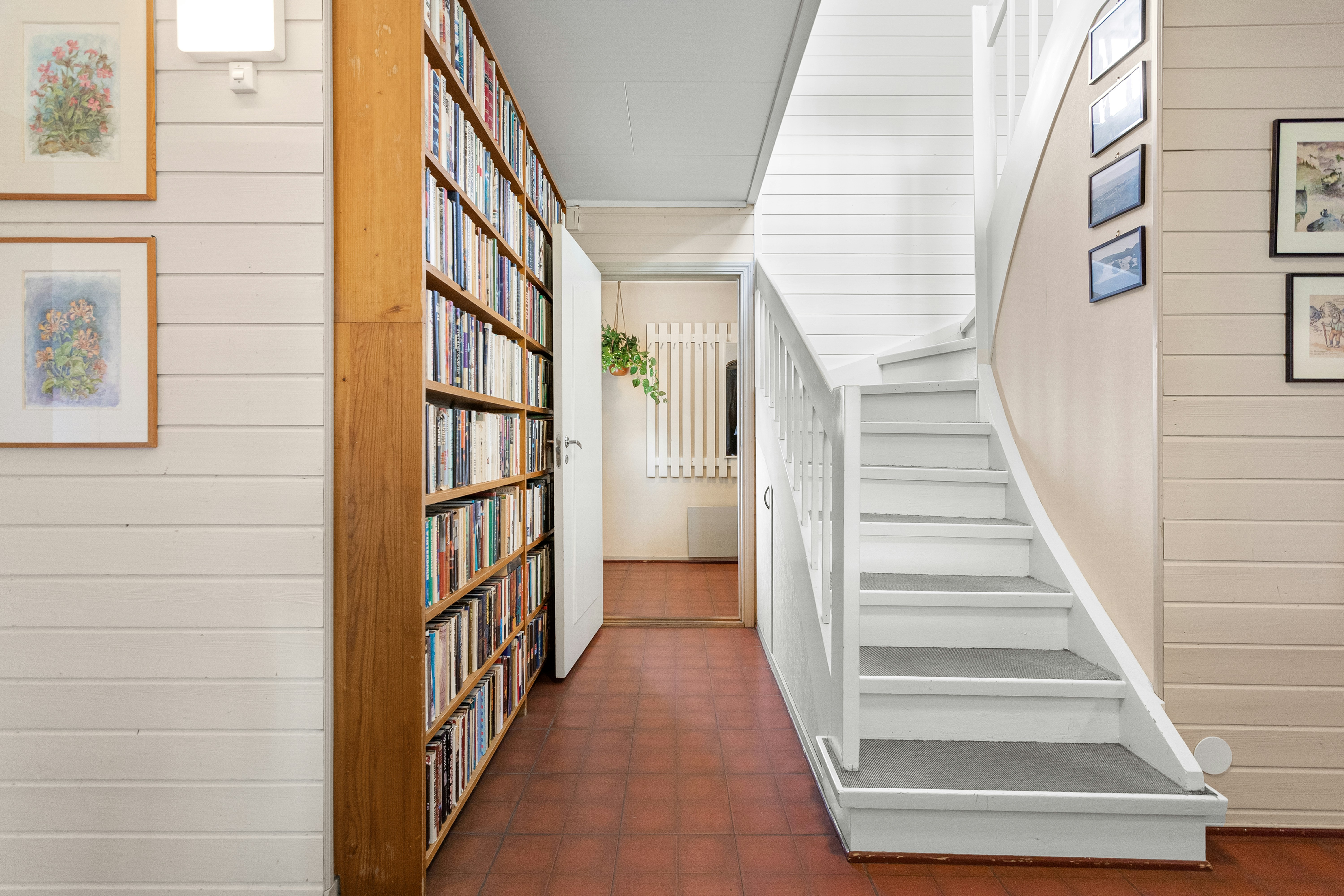 Sunlit Library Corridor: Staircase Framed by a Spine-Lined Wall