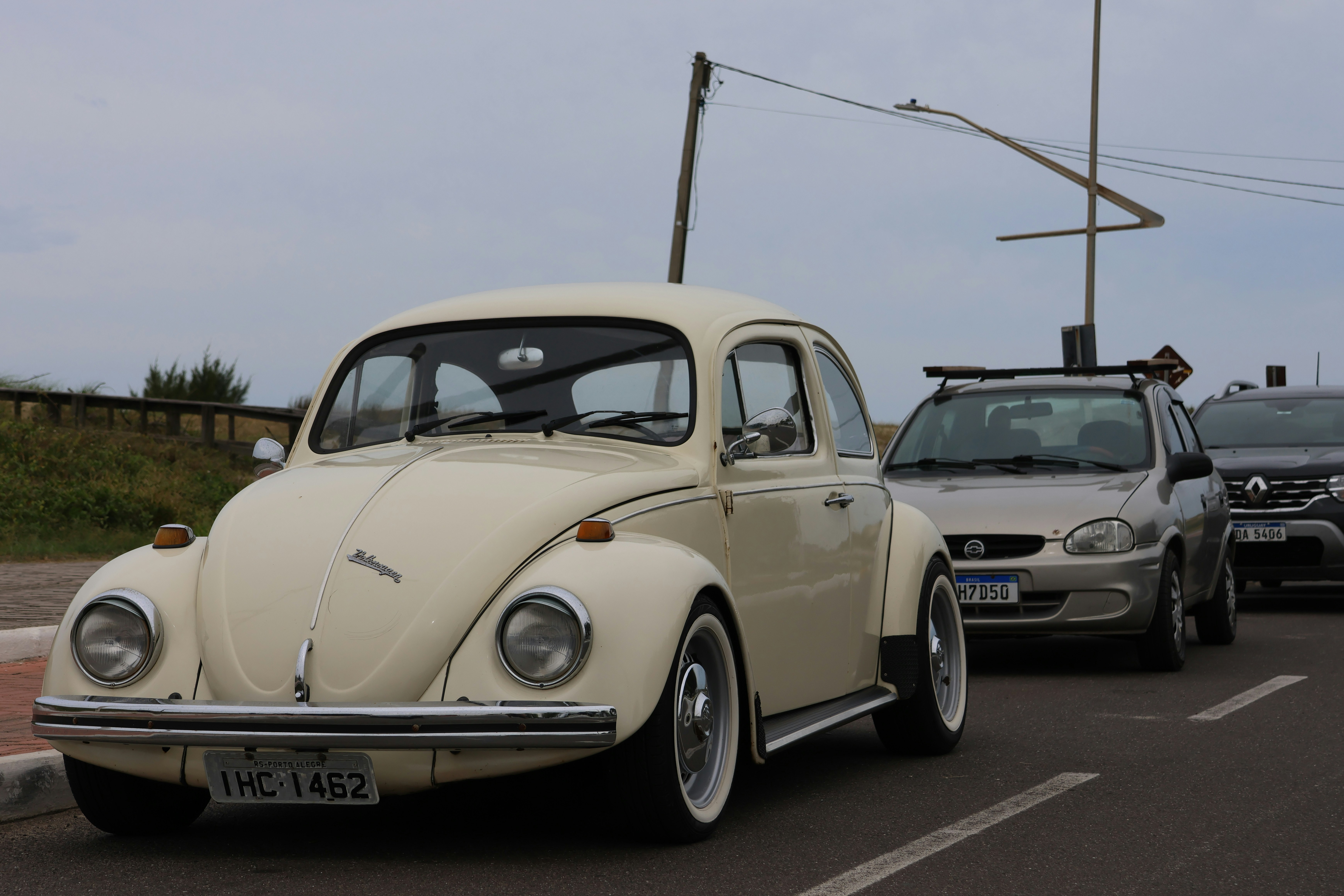 A white vw bug driving down a street next to other cars photo – Free ...