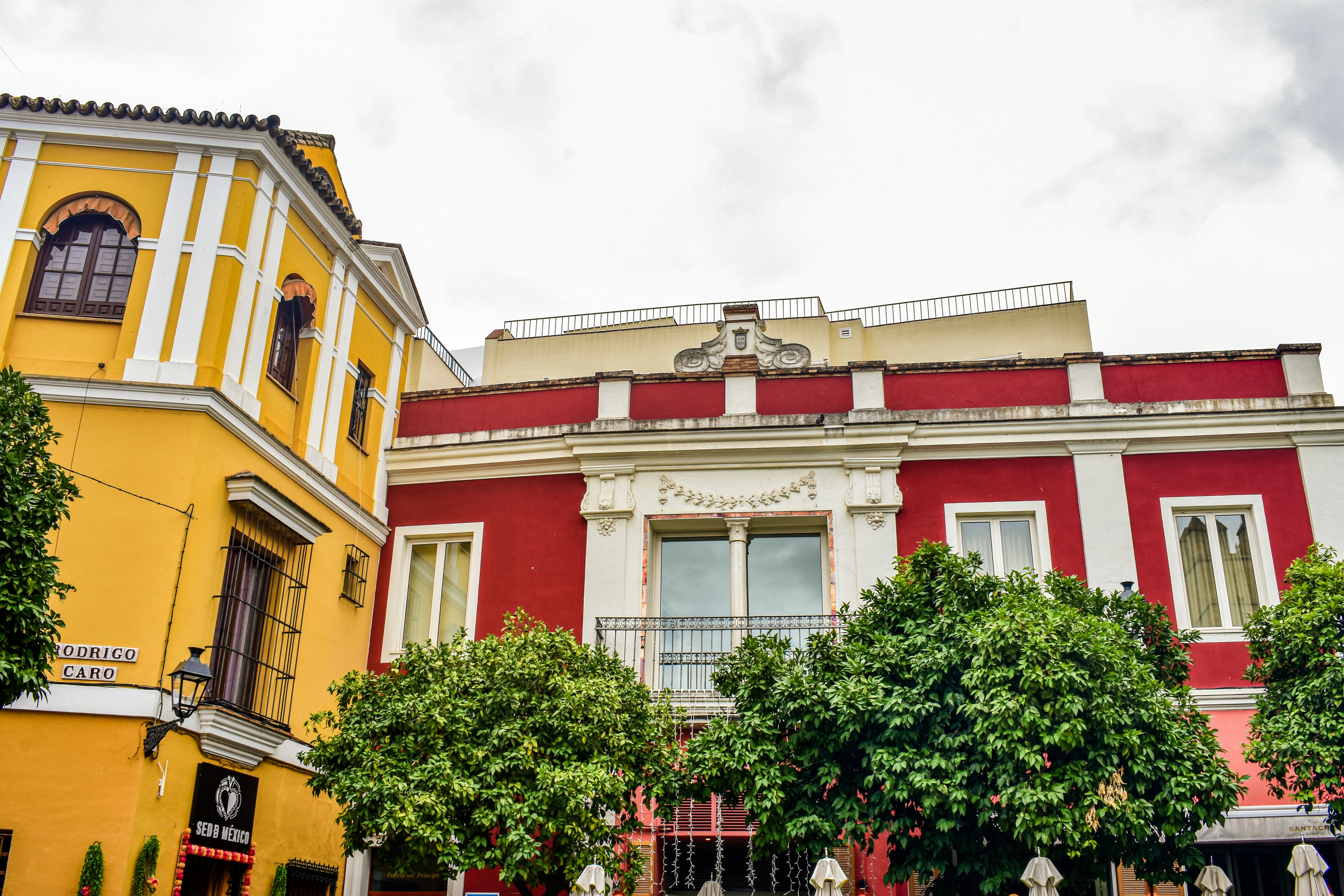 A yellow and red building with trees in front of it photo – Free ...