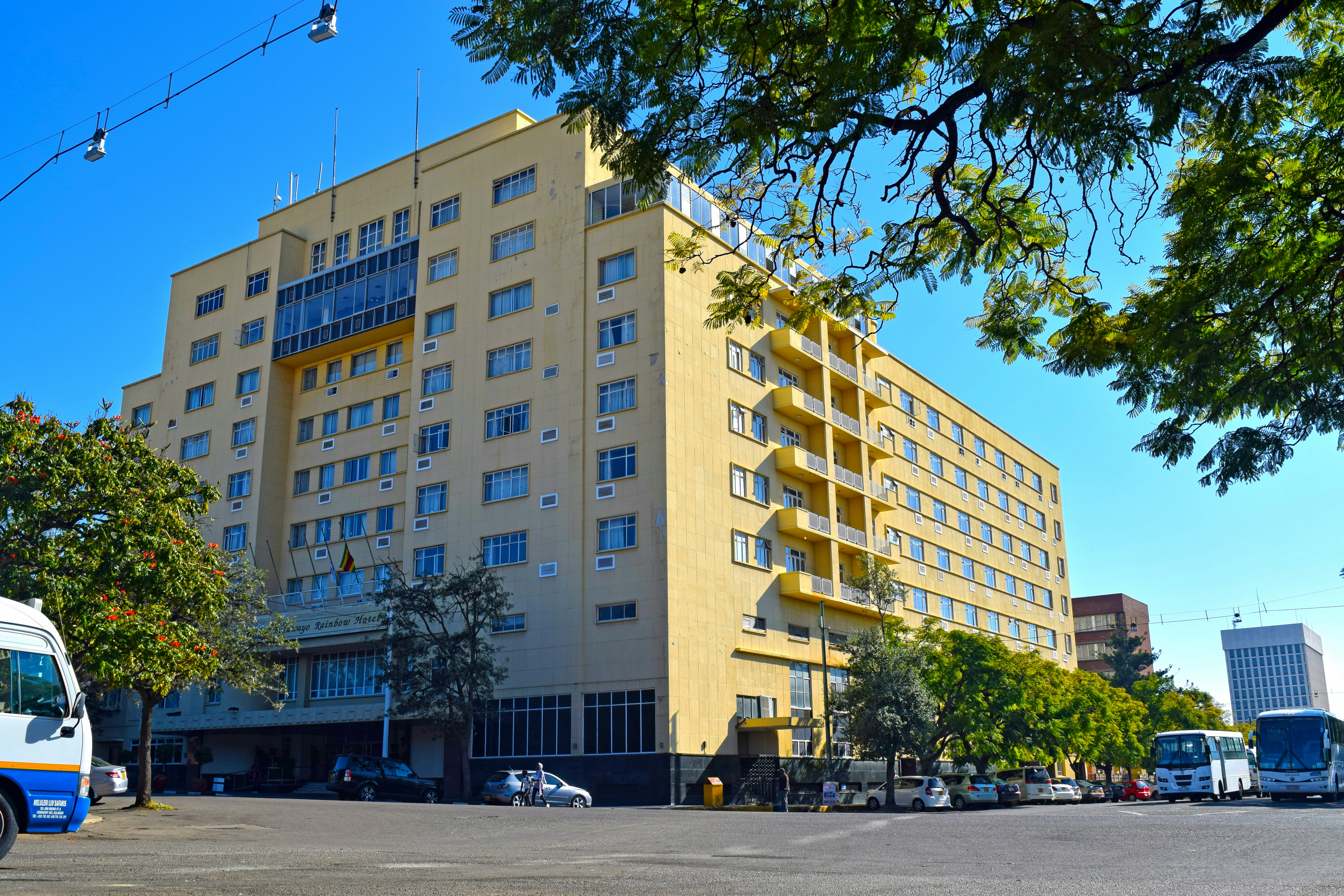 A bus parked in front of a large yellow building photo – Free Bulawayo ...