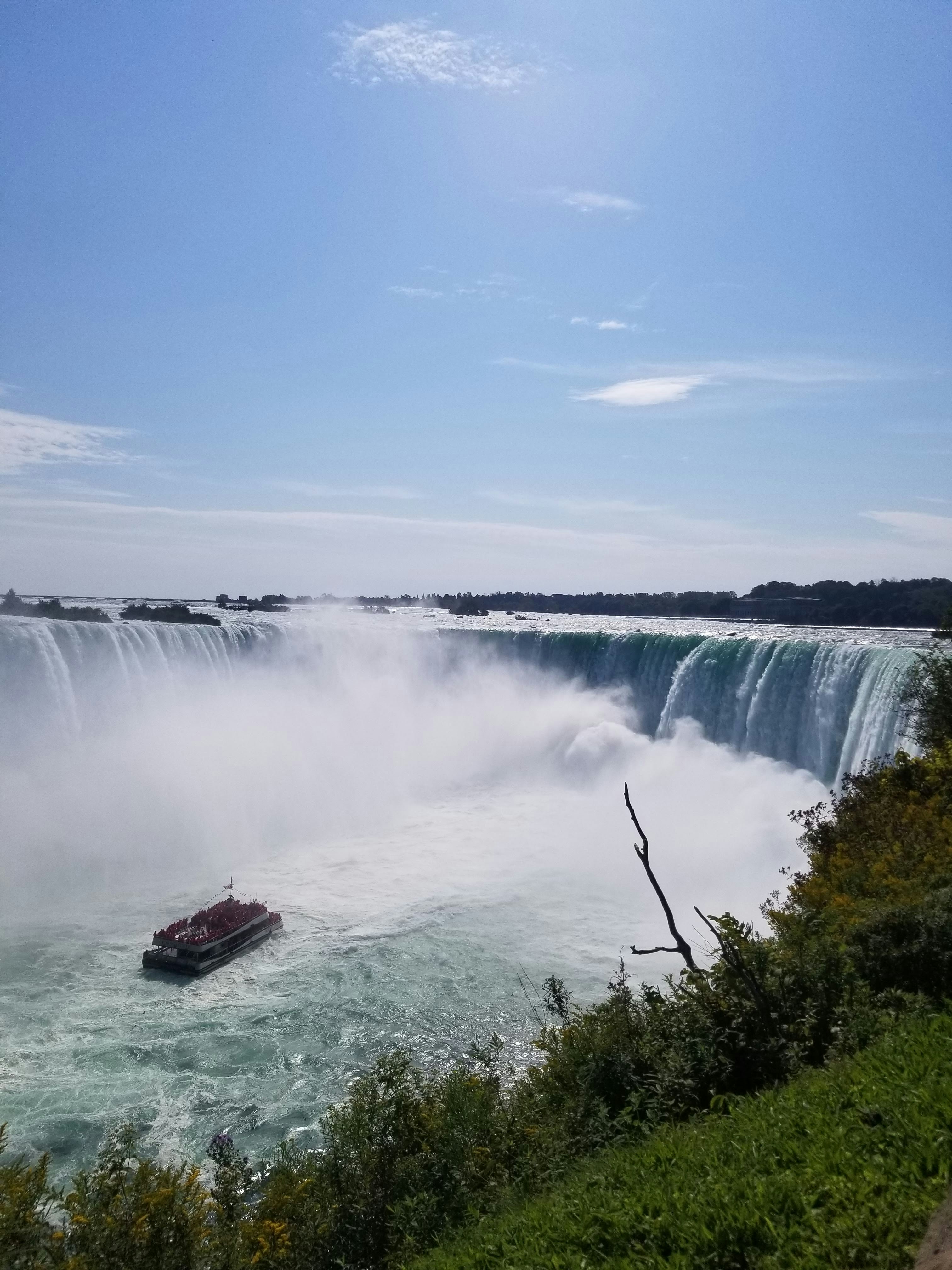 A boat in the water near a large waterfall