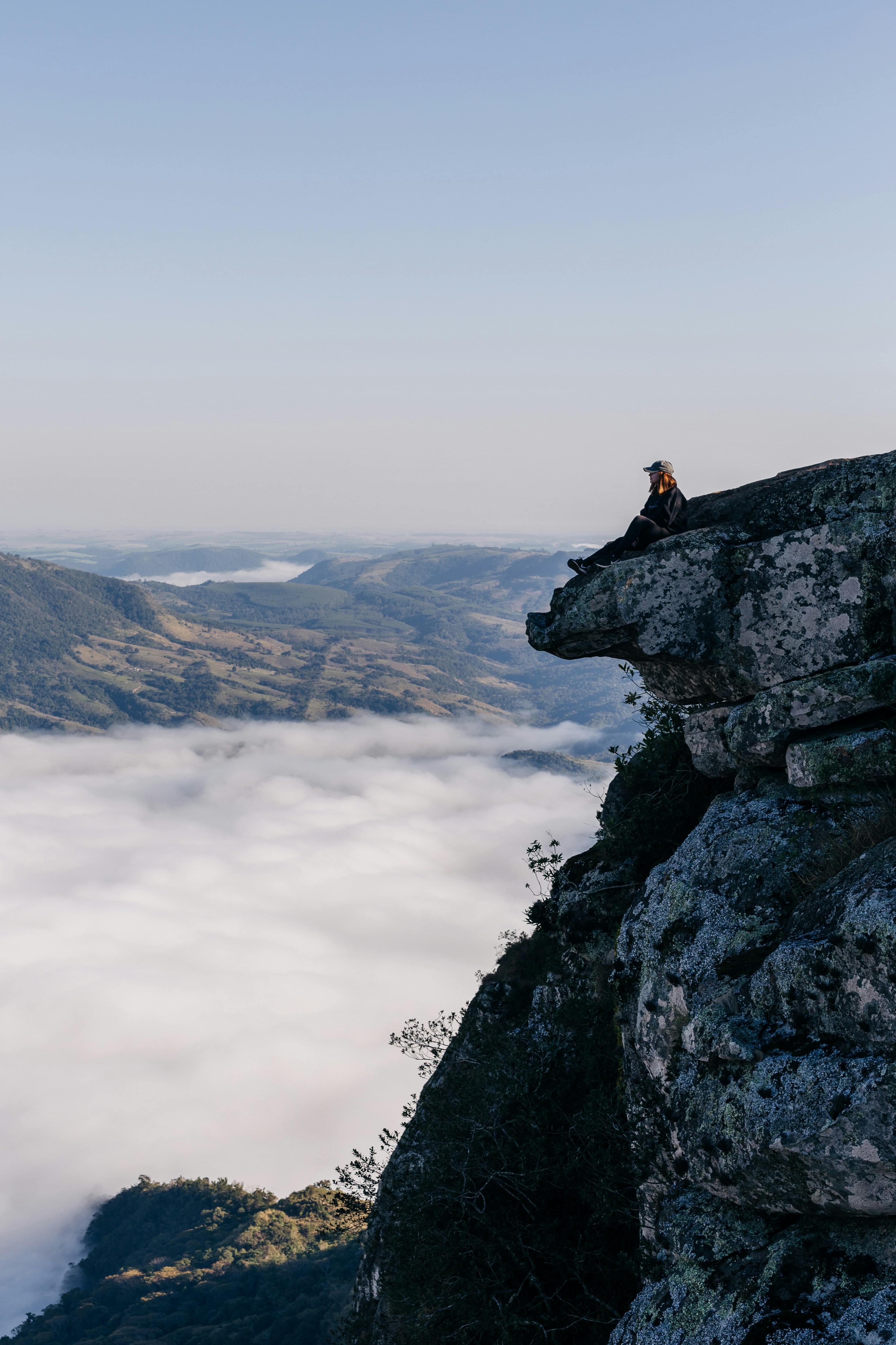 A person sitting on top of a cliff above the clouds photo – Free Nature ...