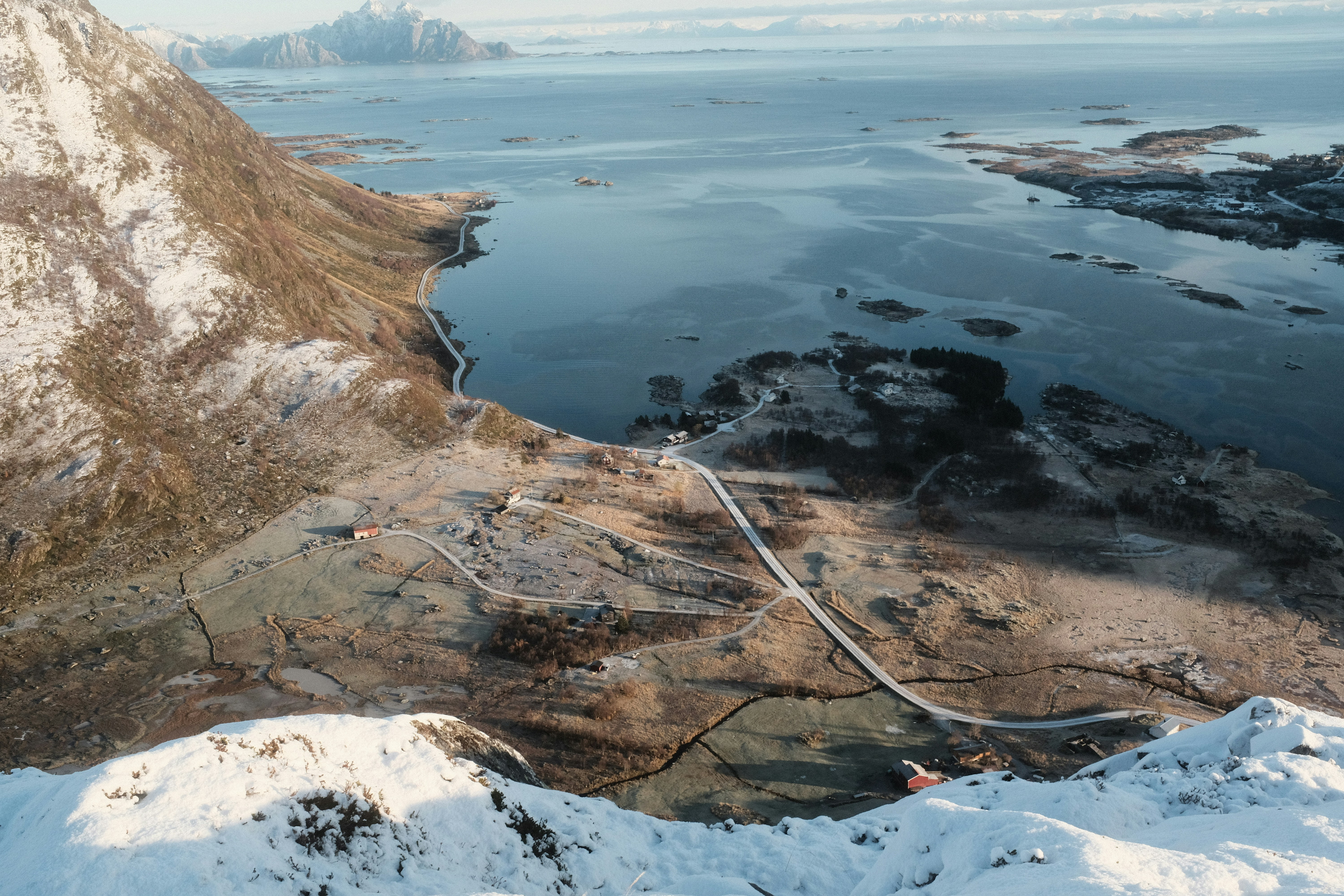 Snow-Kissed Shoreline: A Winding Causeway Tracing the Fjord Edge
