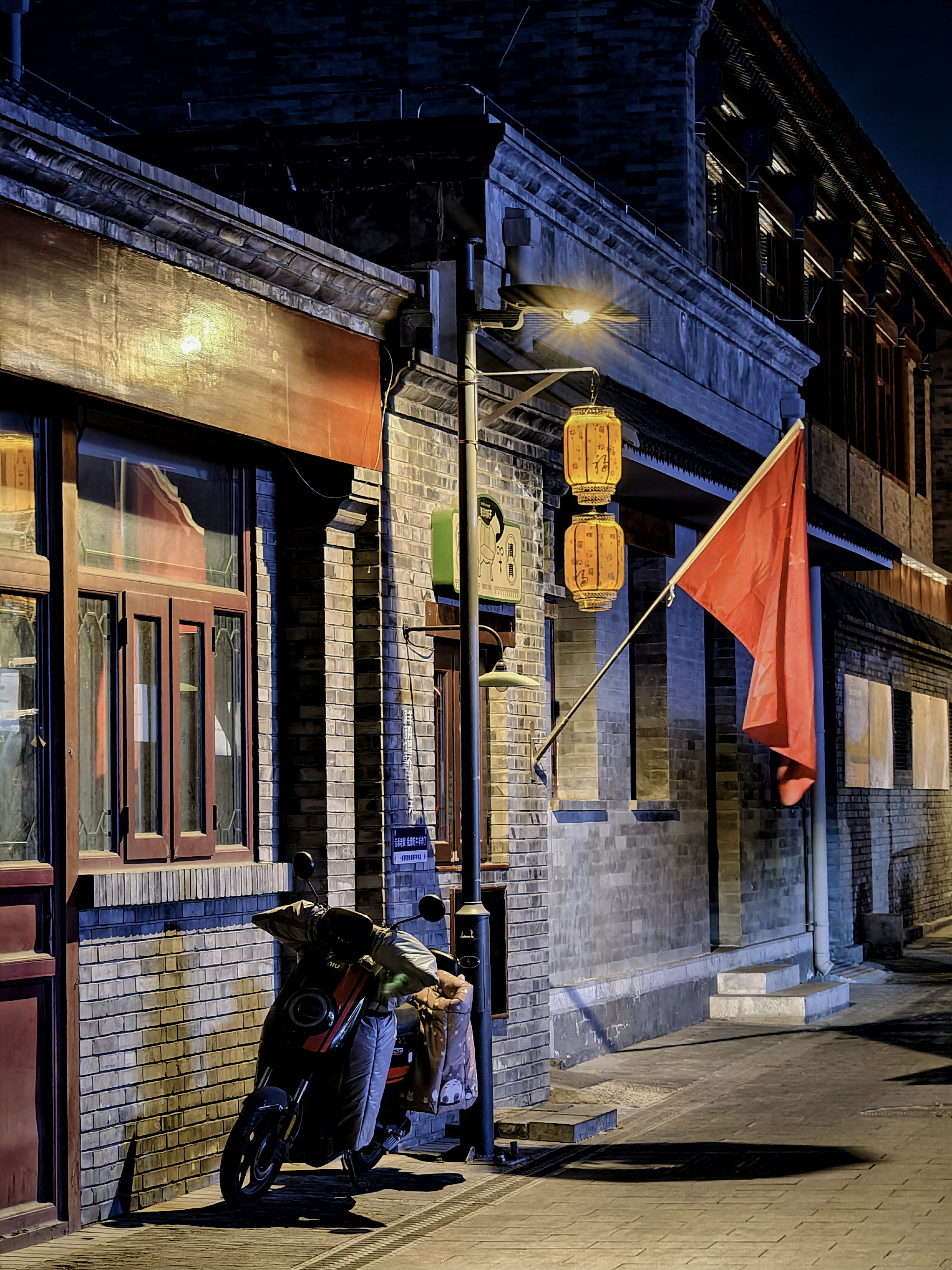 Lantern Street at Night: A Quiet Alley with Red Flag and Scooter