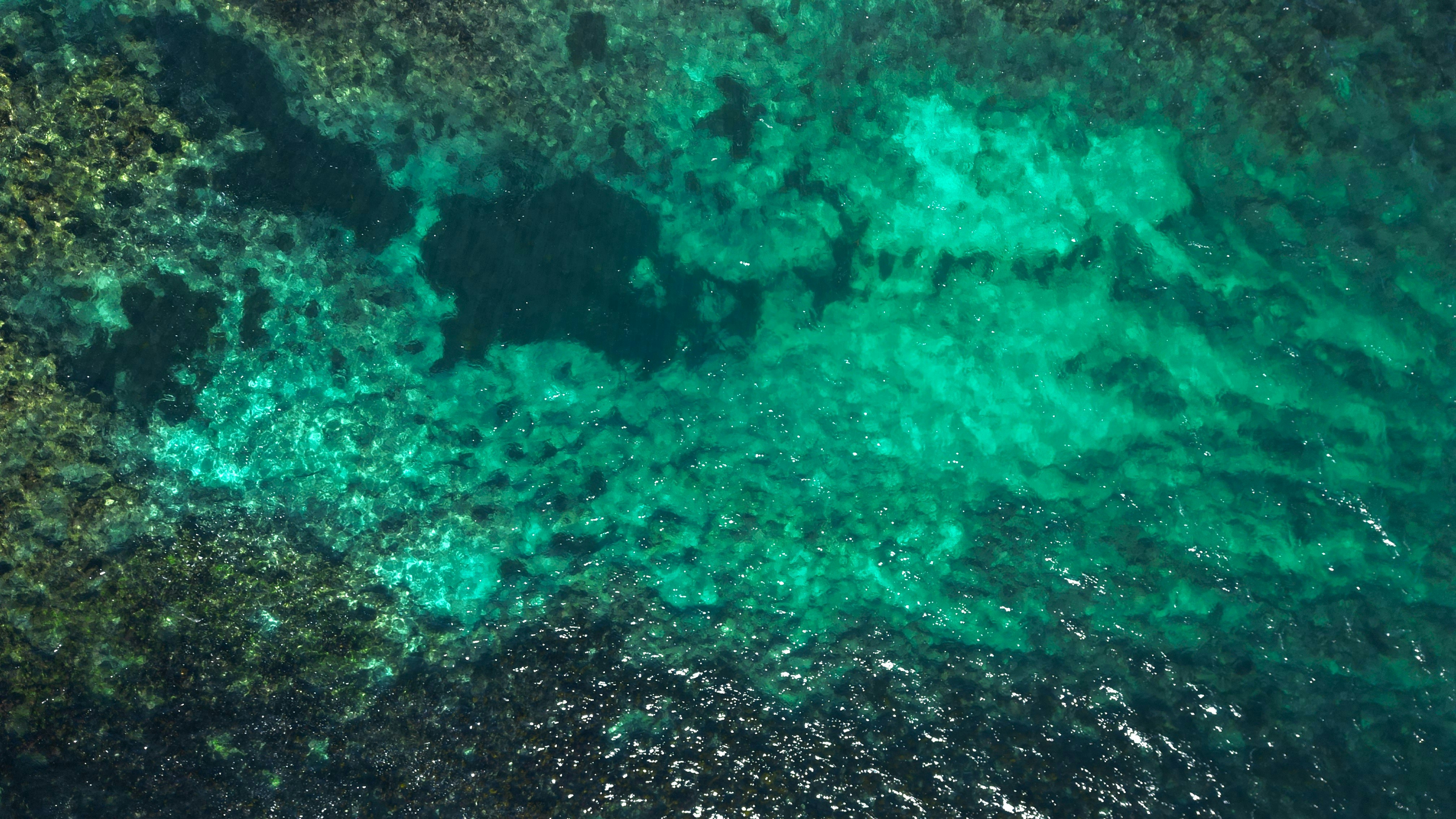 Aerial view of the sea stirring up the sand on the seabed | An aerial view of a body of water