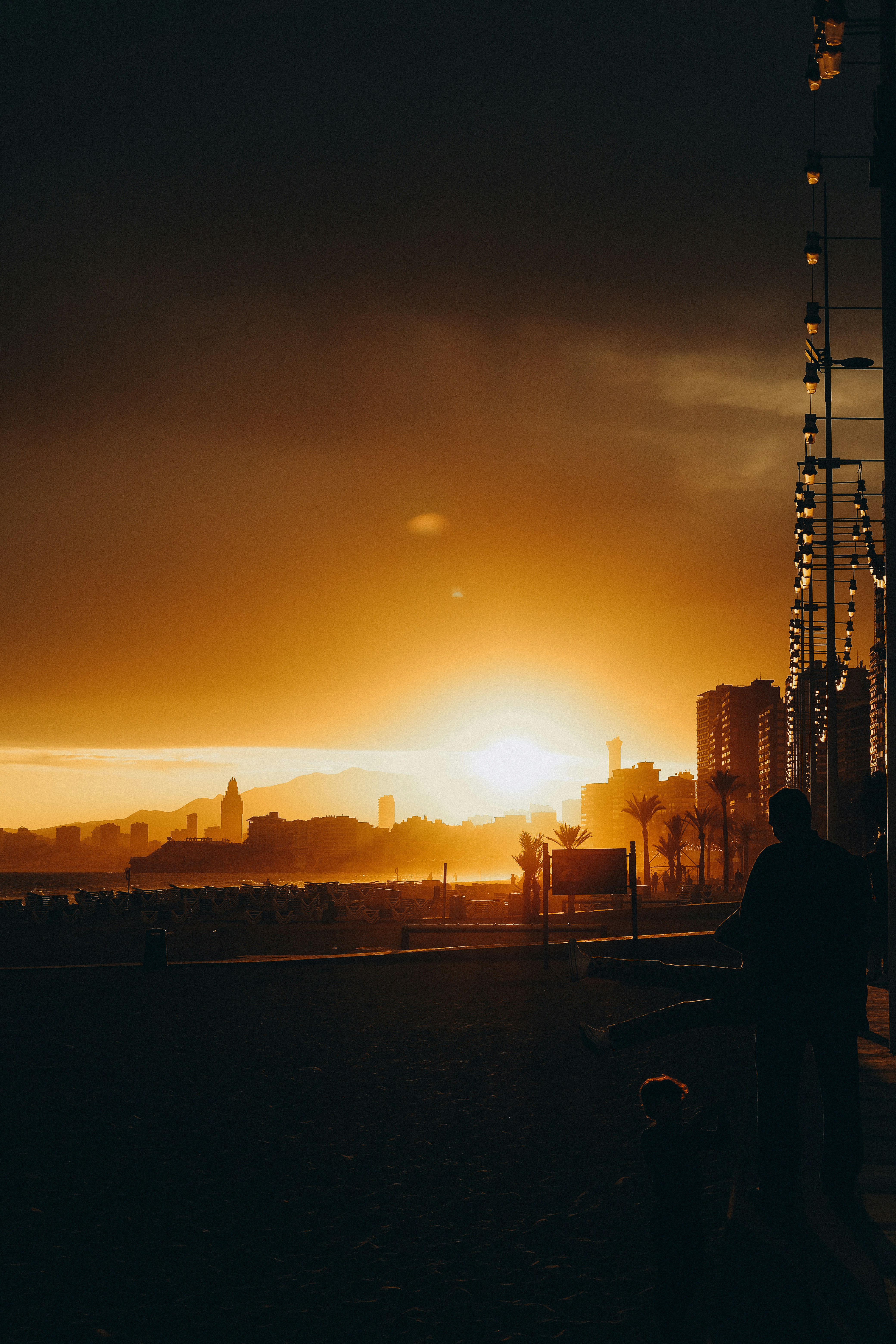 A person standing on a sidewalk in front of a sunset photo – Free ...