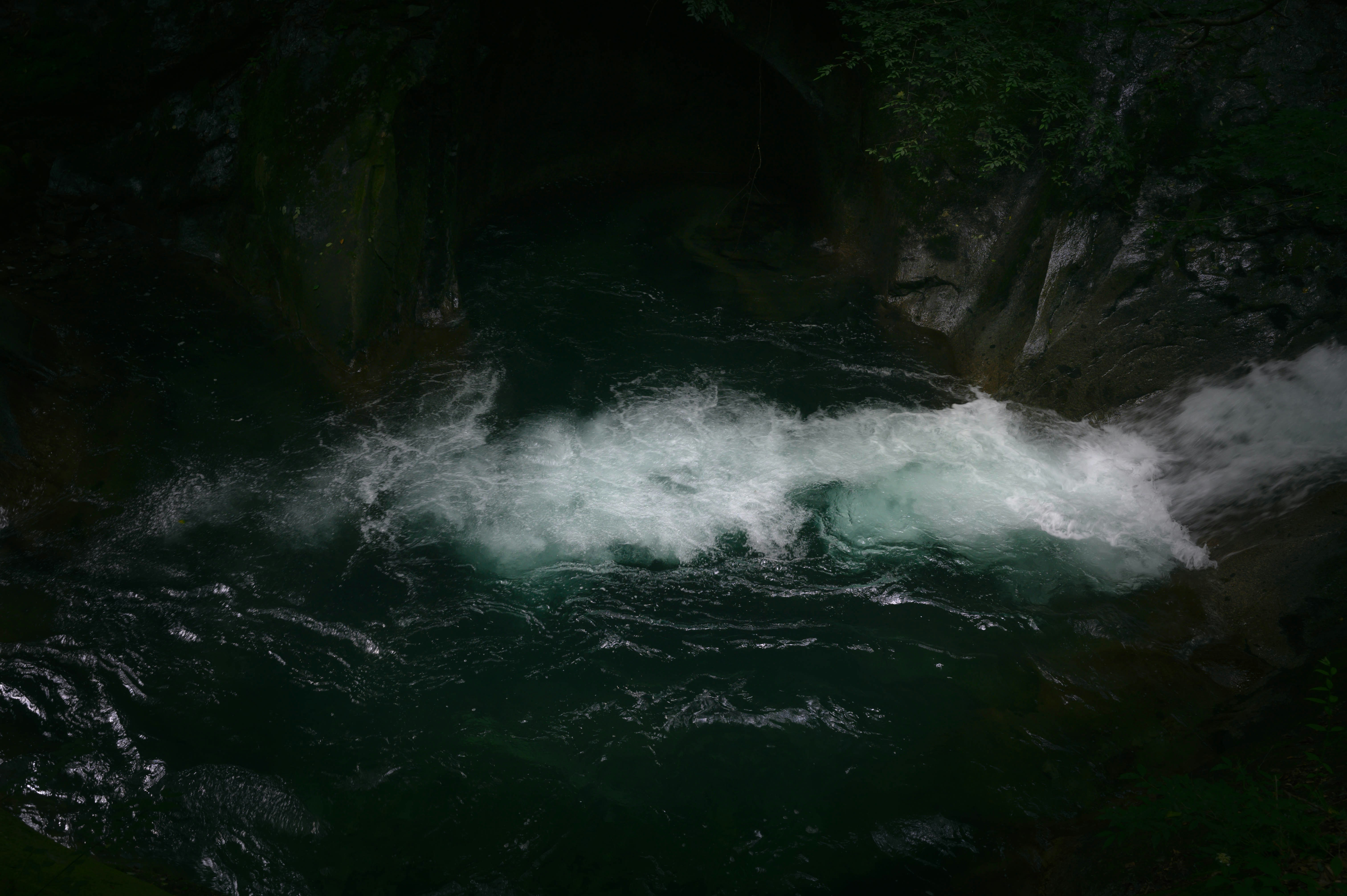 Veiled Gorge: White Wake Carving Through Shadowed Currents