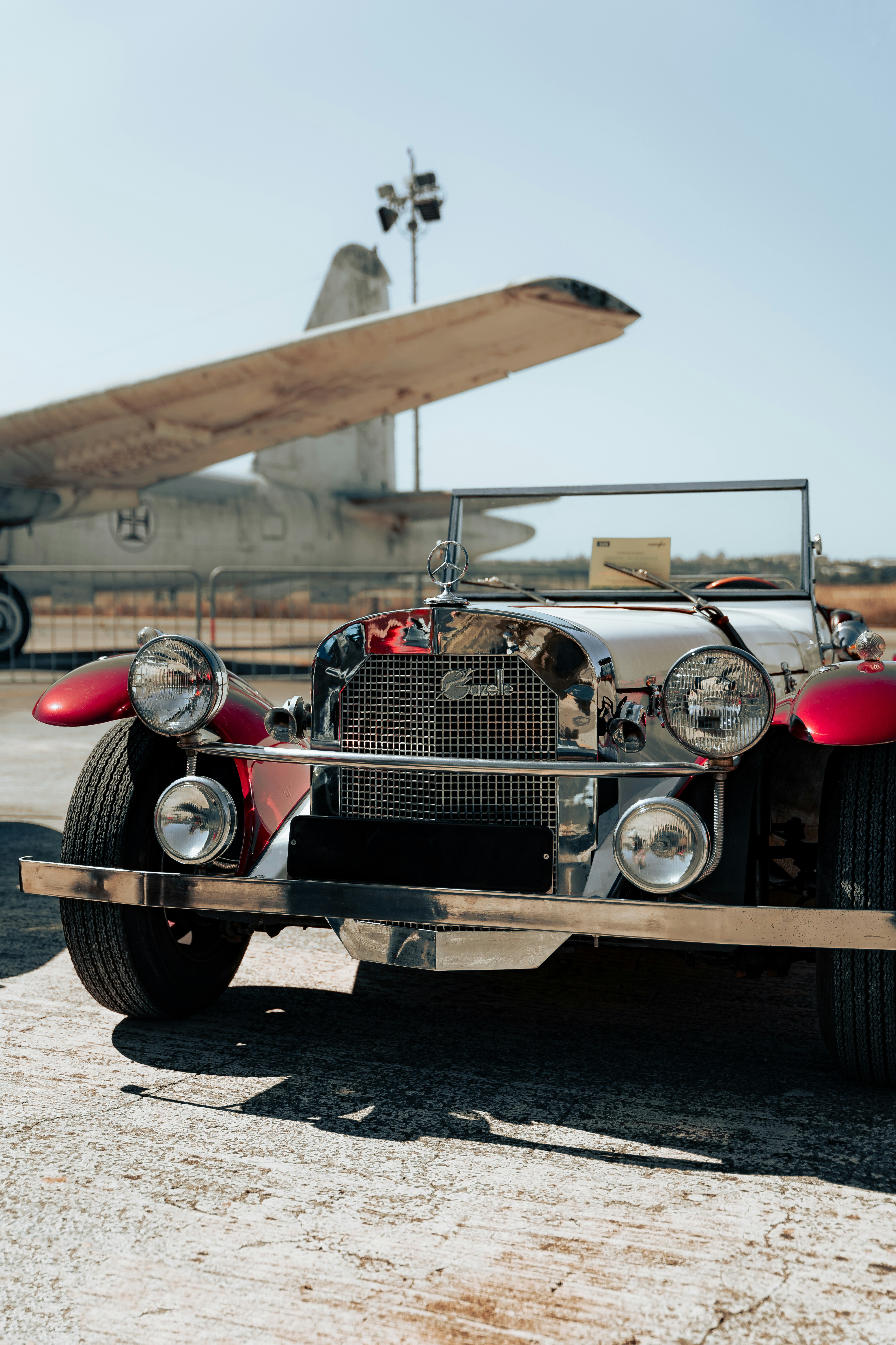 Chrome and gables: vintage roadster with aircraft in the background