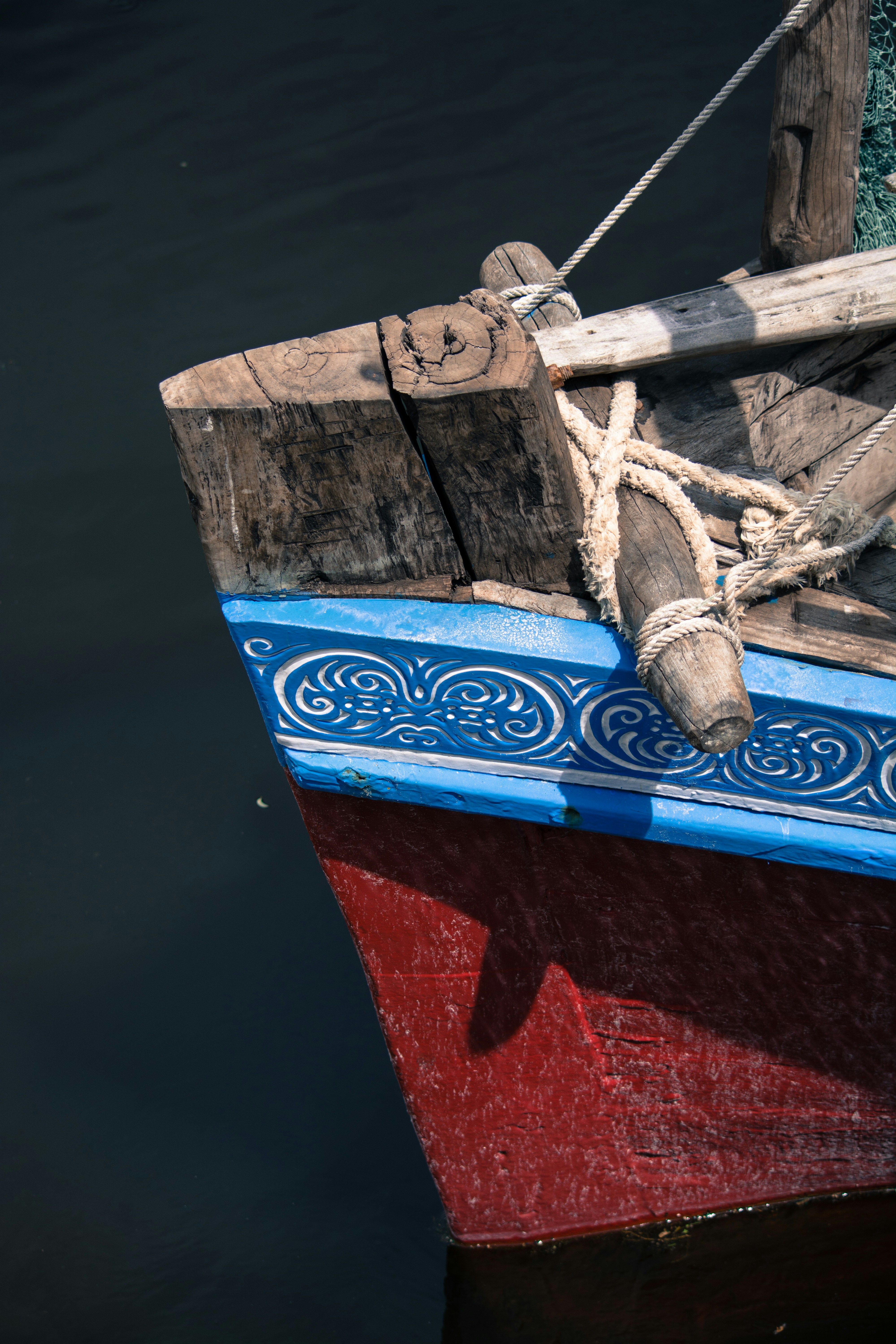 Cobalt Scrolls on a Red Hull: Close-Up of a Weathered Boat Bow