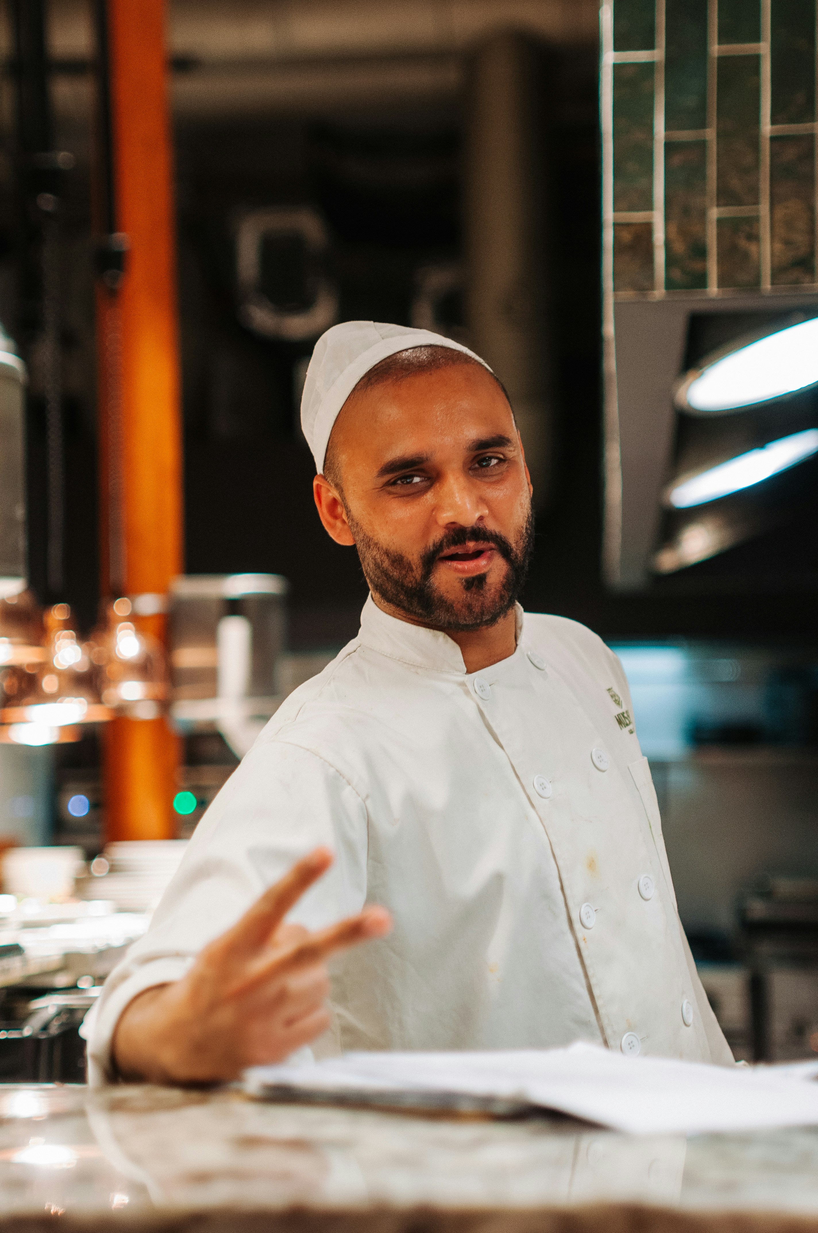 A man in a chef's outfit standing in front of a counter photo – Free ...