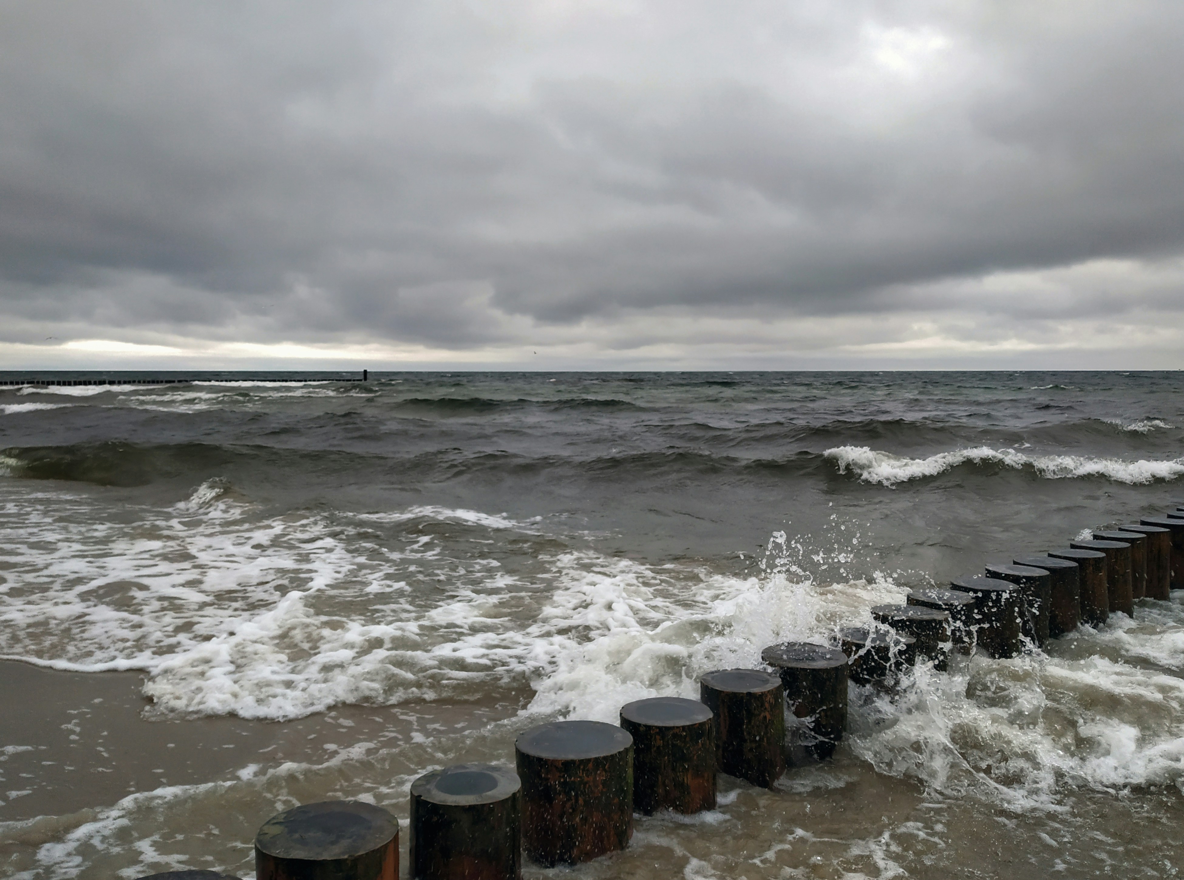Pilings at the Edge: Waves Clash Along a Grey Shore