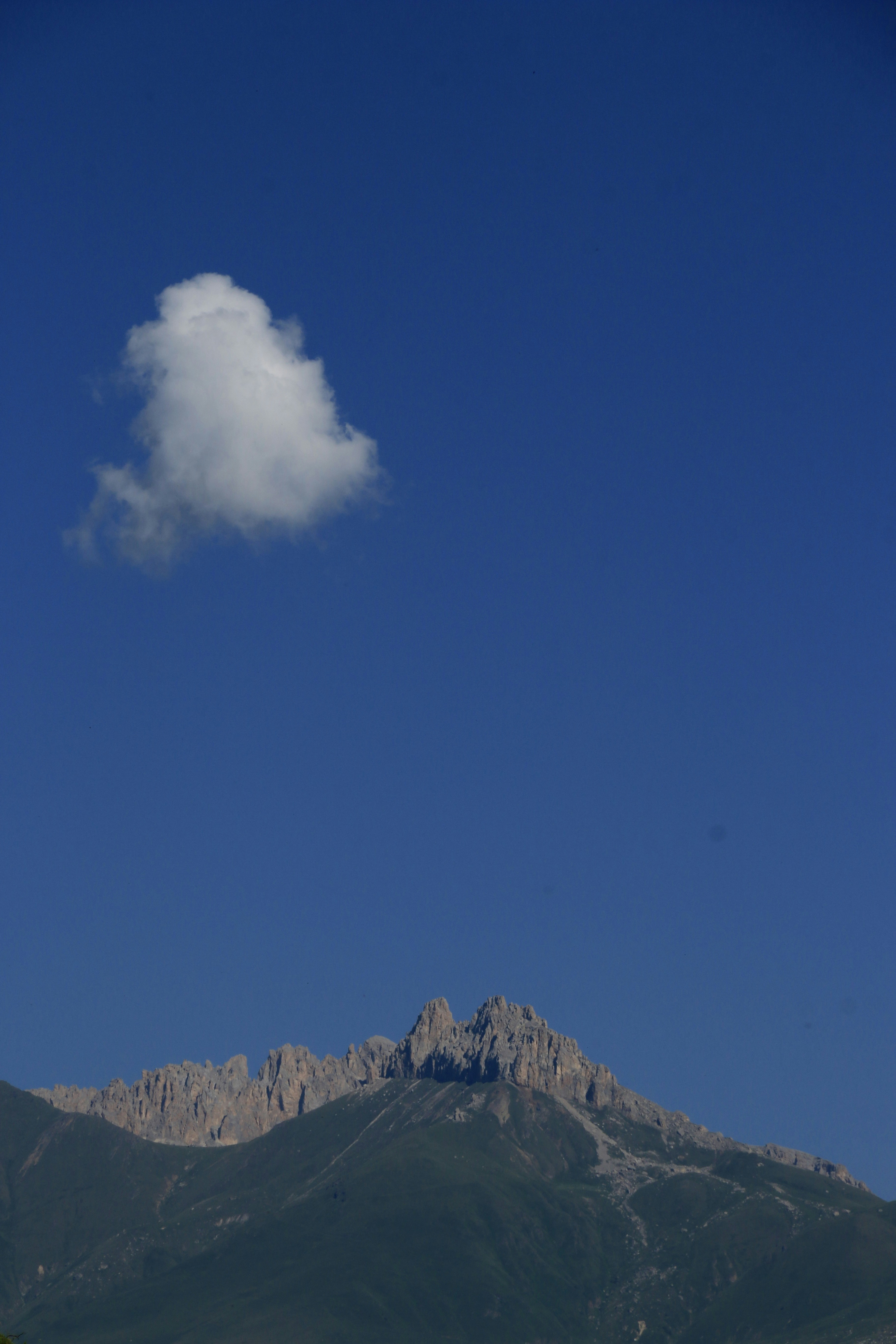 Alpine Crest under a Pristine Blue Sky with a Lone Cloud