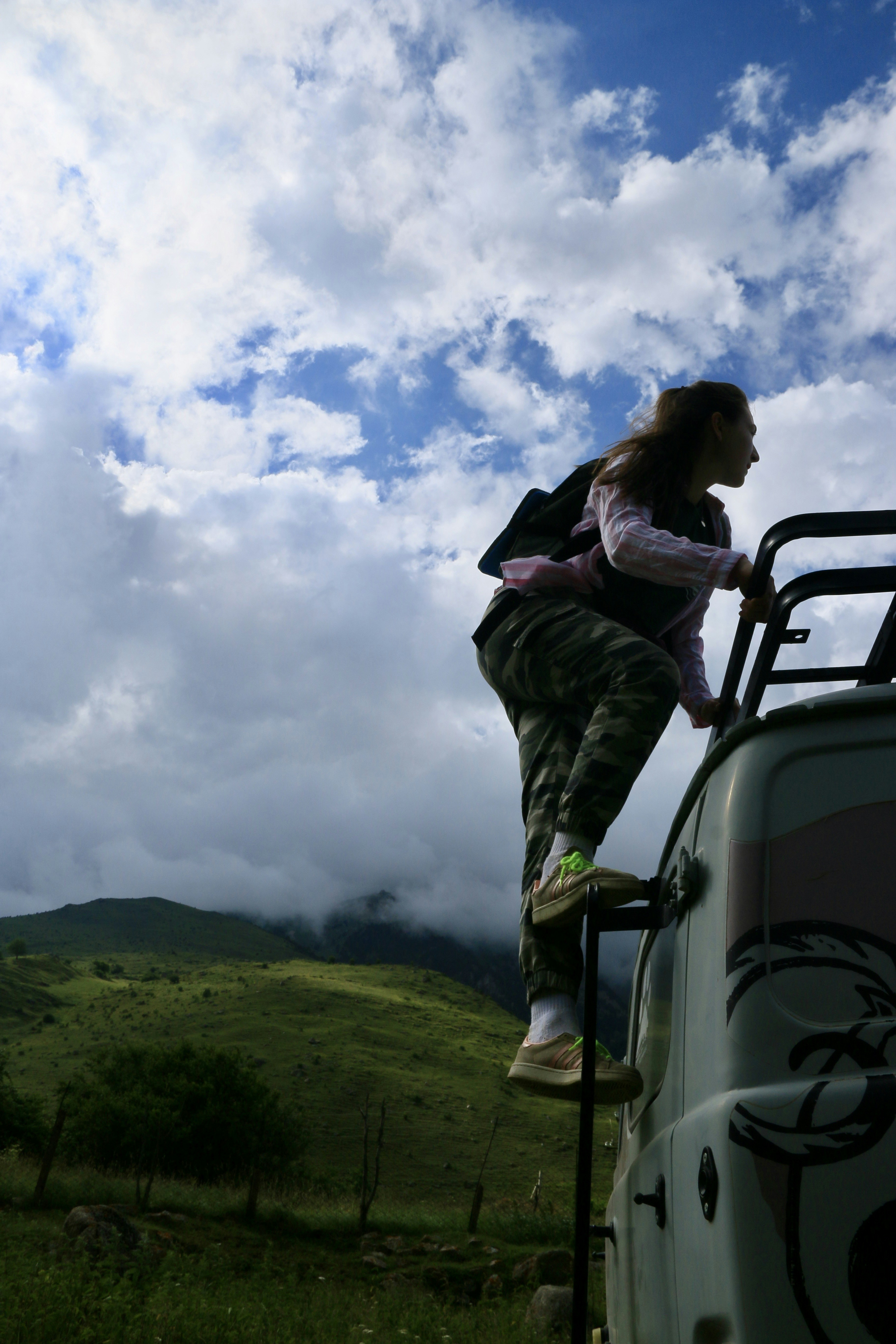 Climber on a Painted Bus Against a Cloud-Swept Valley