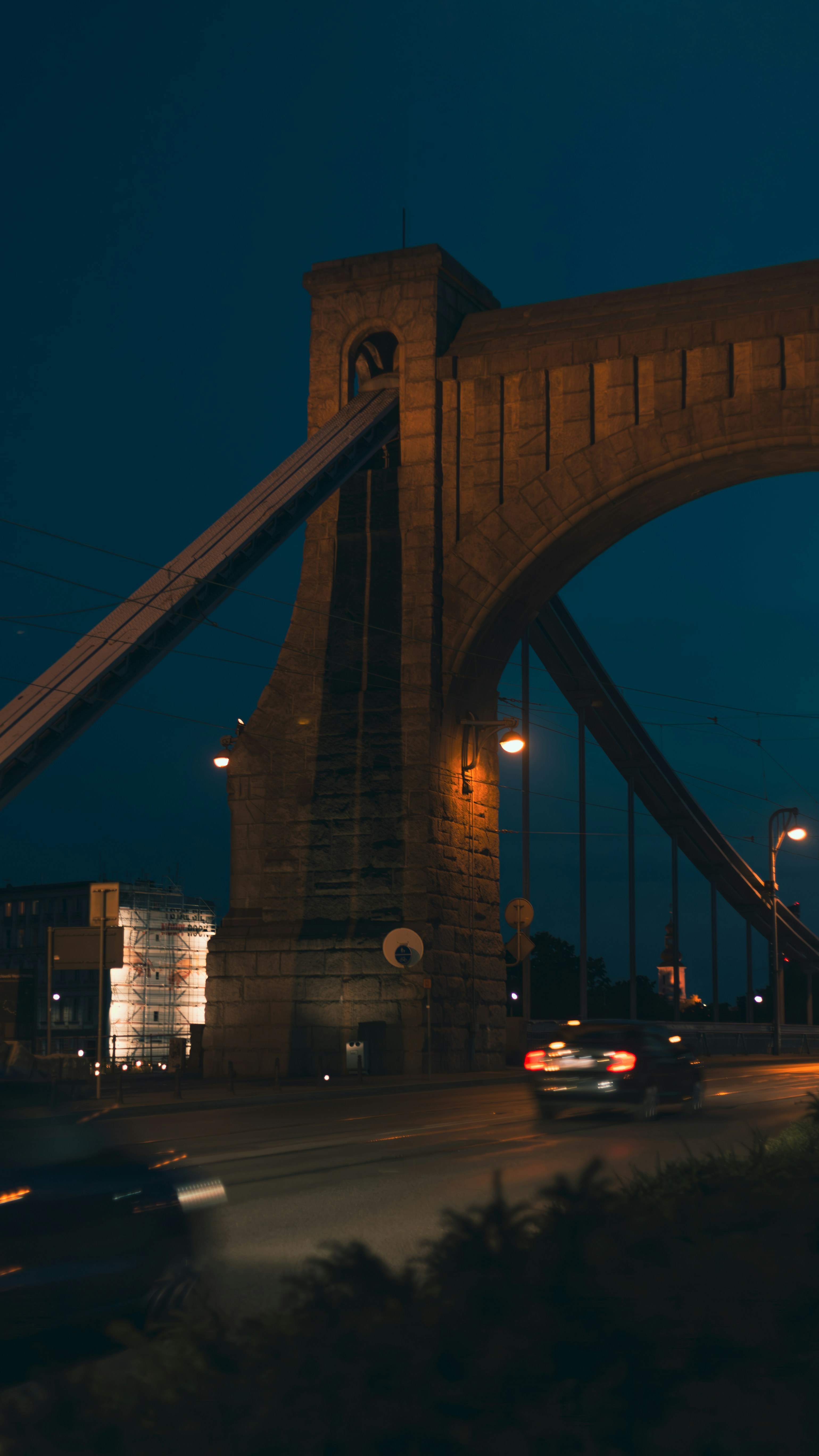 Nocturnal Arc: Warm Lamps Embrace a Stone Suspension Bridge