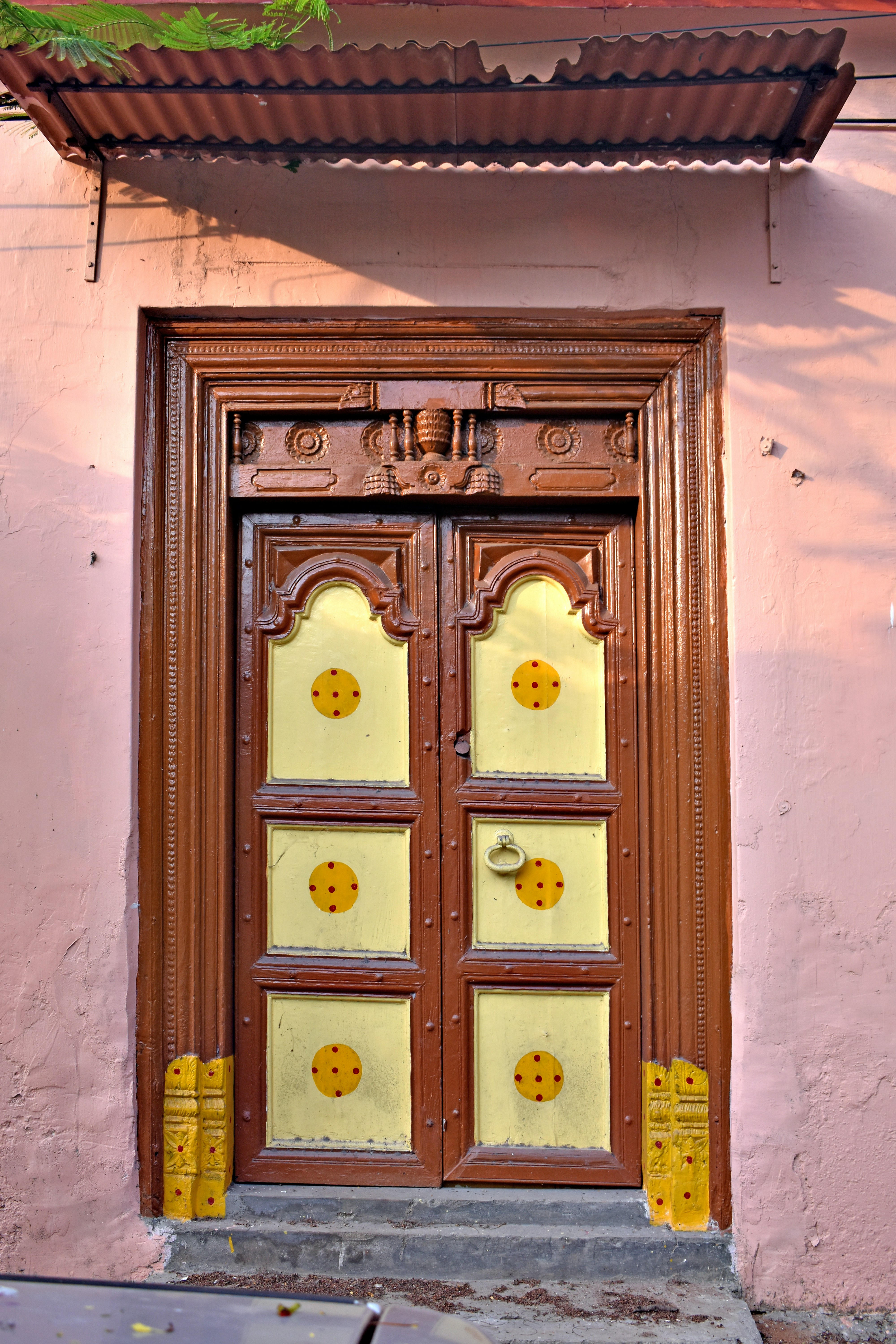 Pastel Portal: Ornate Brown Door with Yellow Inset Panels on a Pink Facade