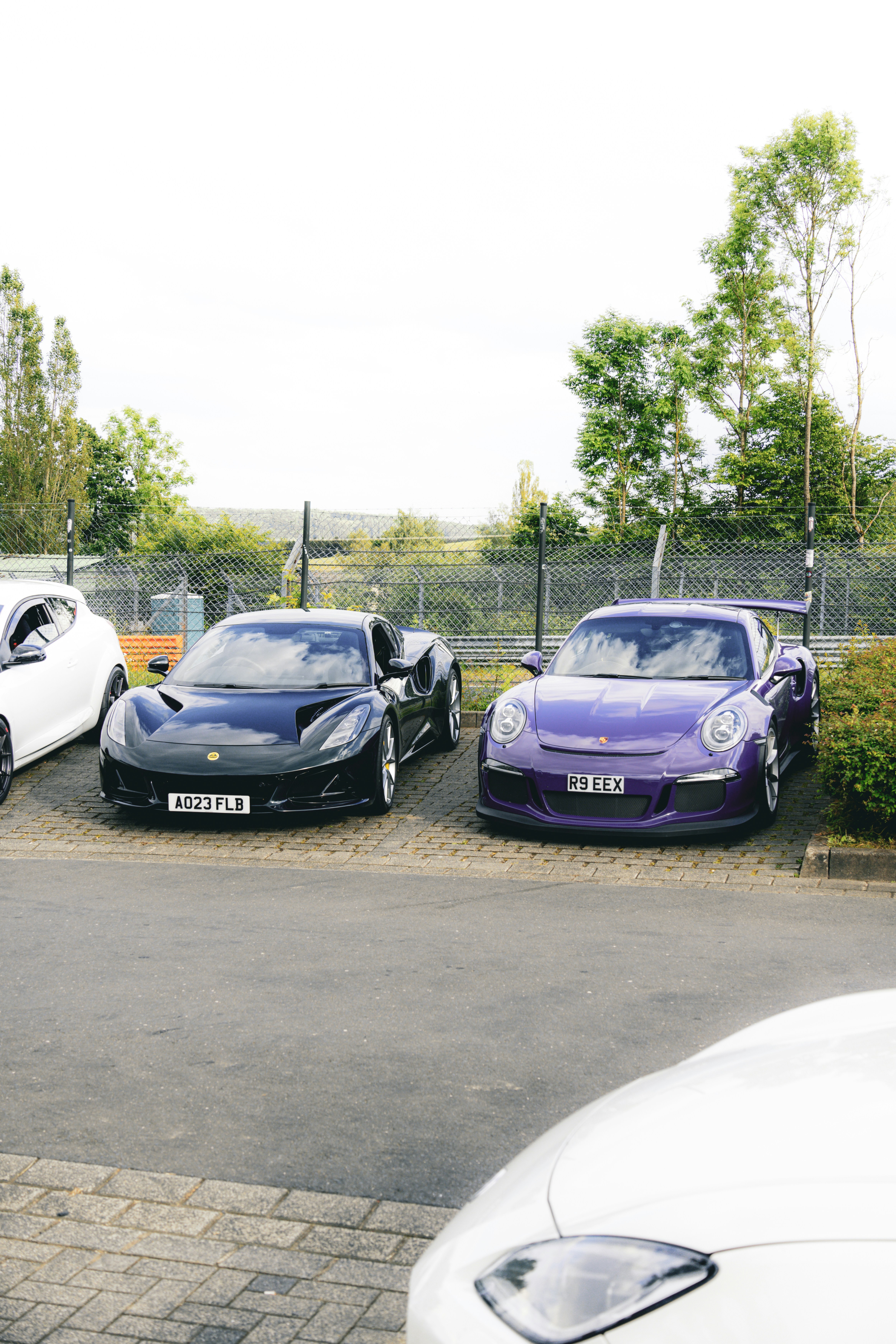 Purple thunder: a row of high-end sports cars in front of a chain-link fence