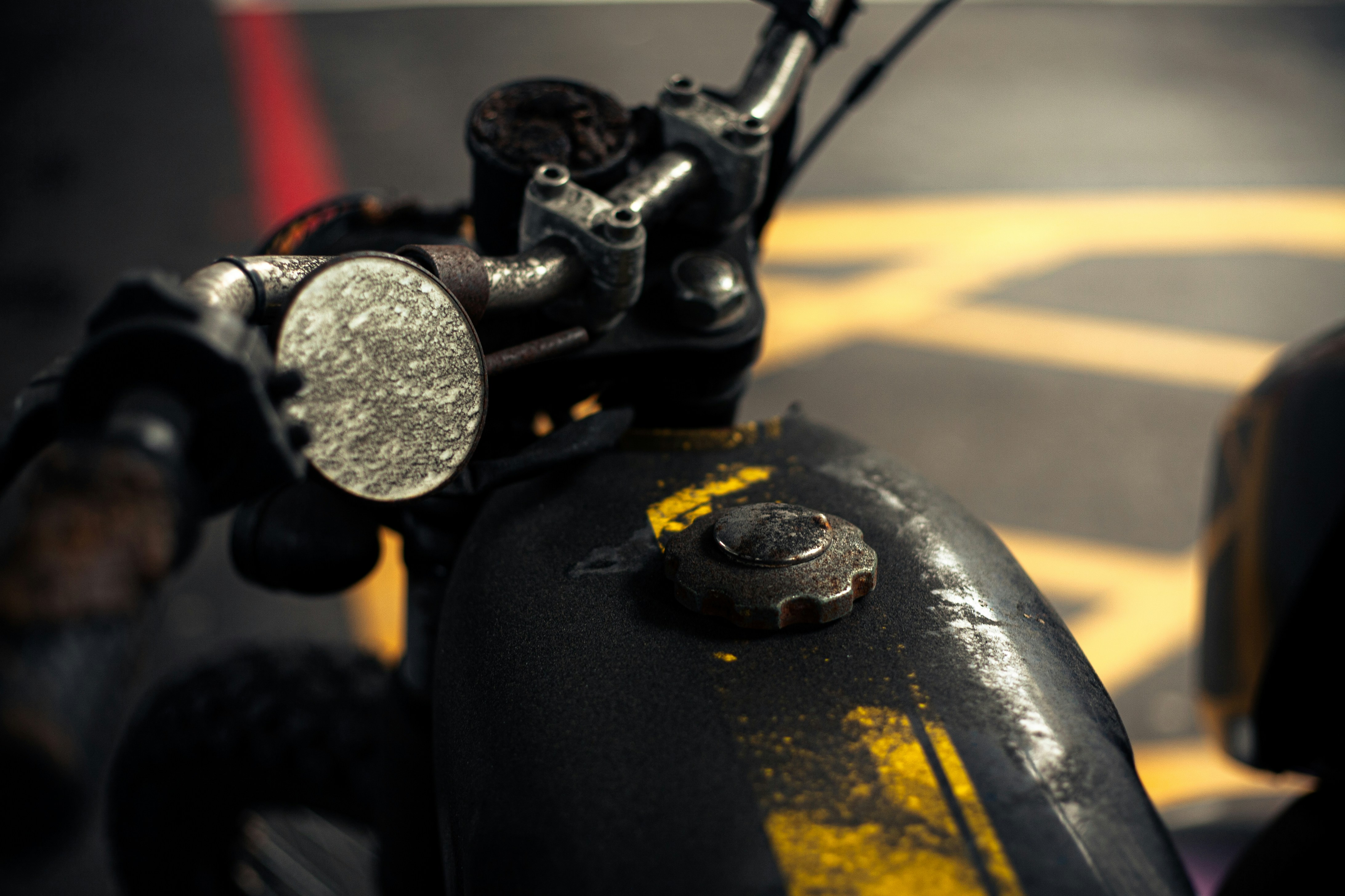 Patina Under Yellow Stripes: Close-Up of a Weathered Motorcycle Tank Cap