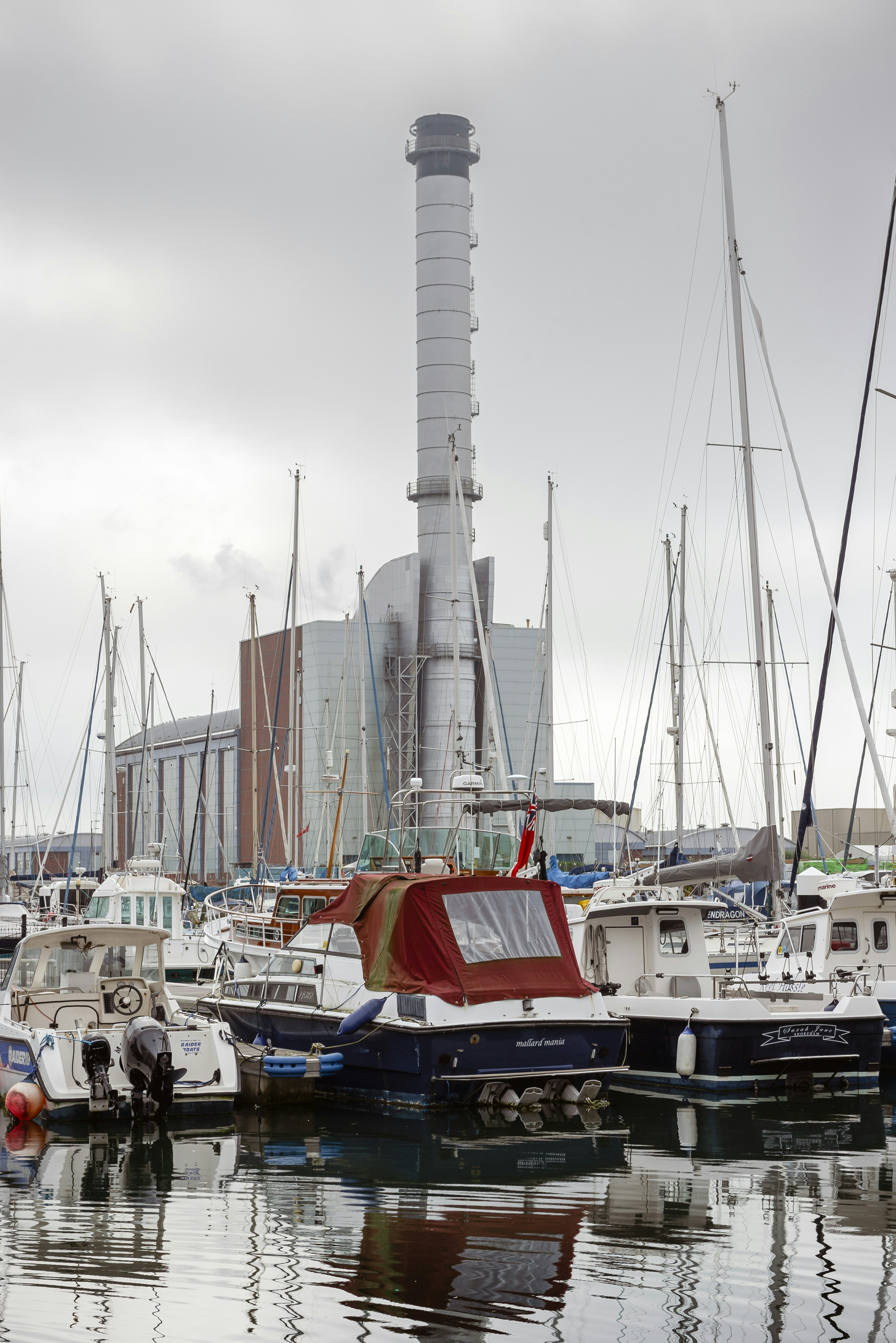 A harbor filled with lots of boats next to a factory photo – Free ...
