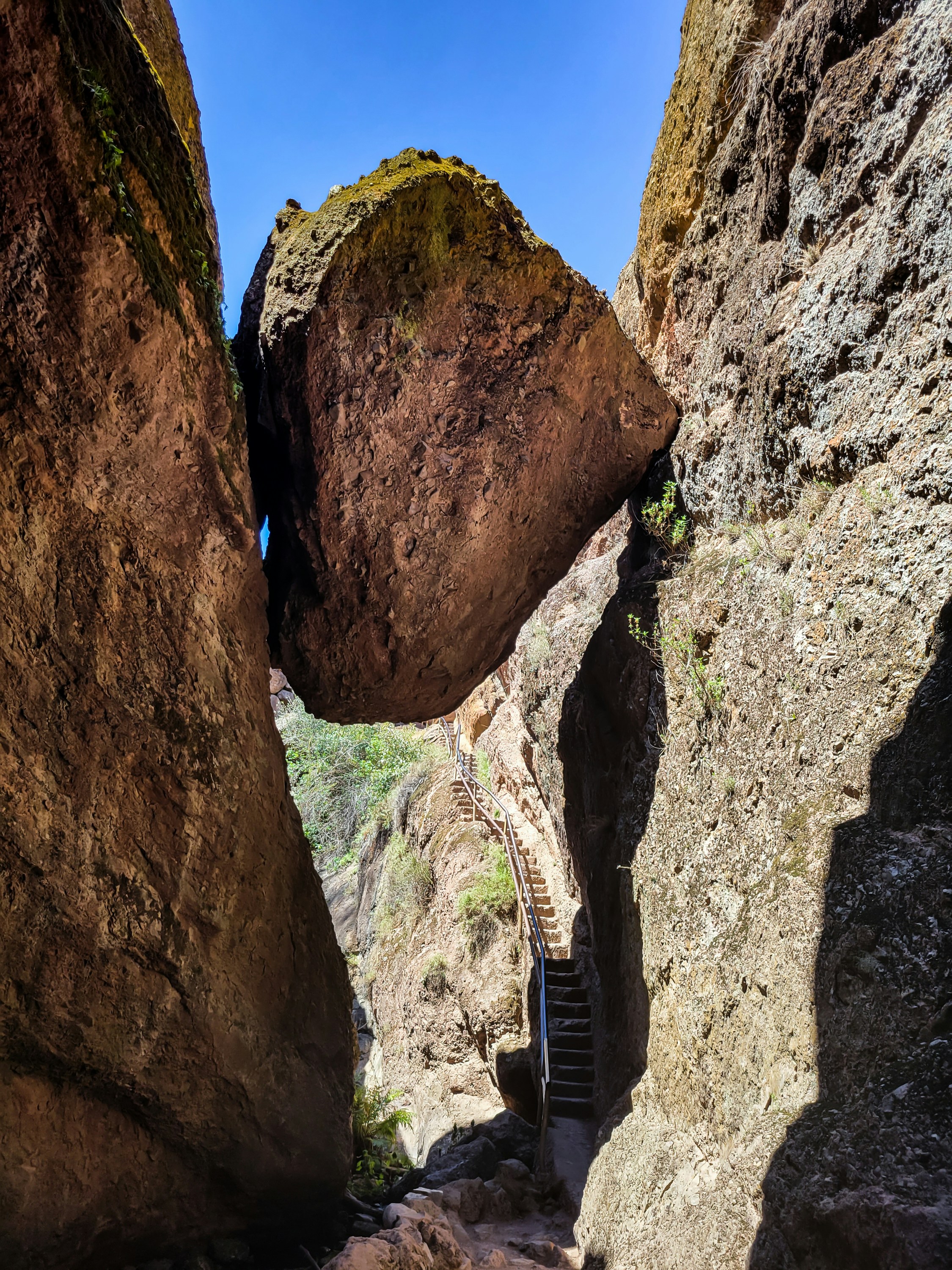 Gravity's Ledger: A Boulder Suspended Between Narrow Cliffs