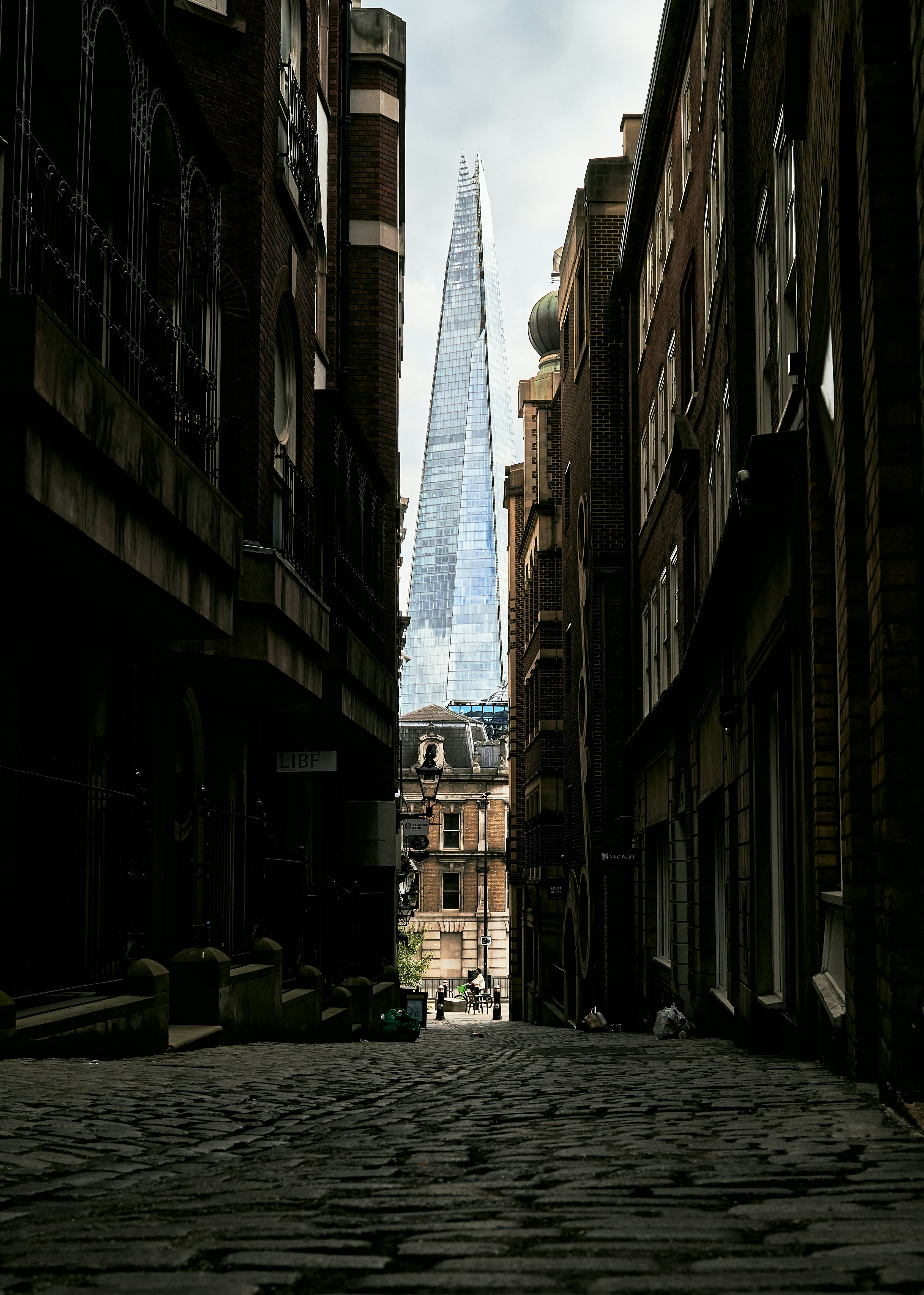A narrow cobblestone street with a tall building in the background ...