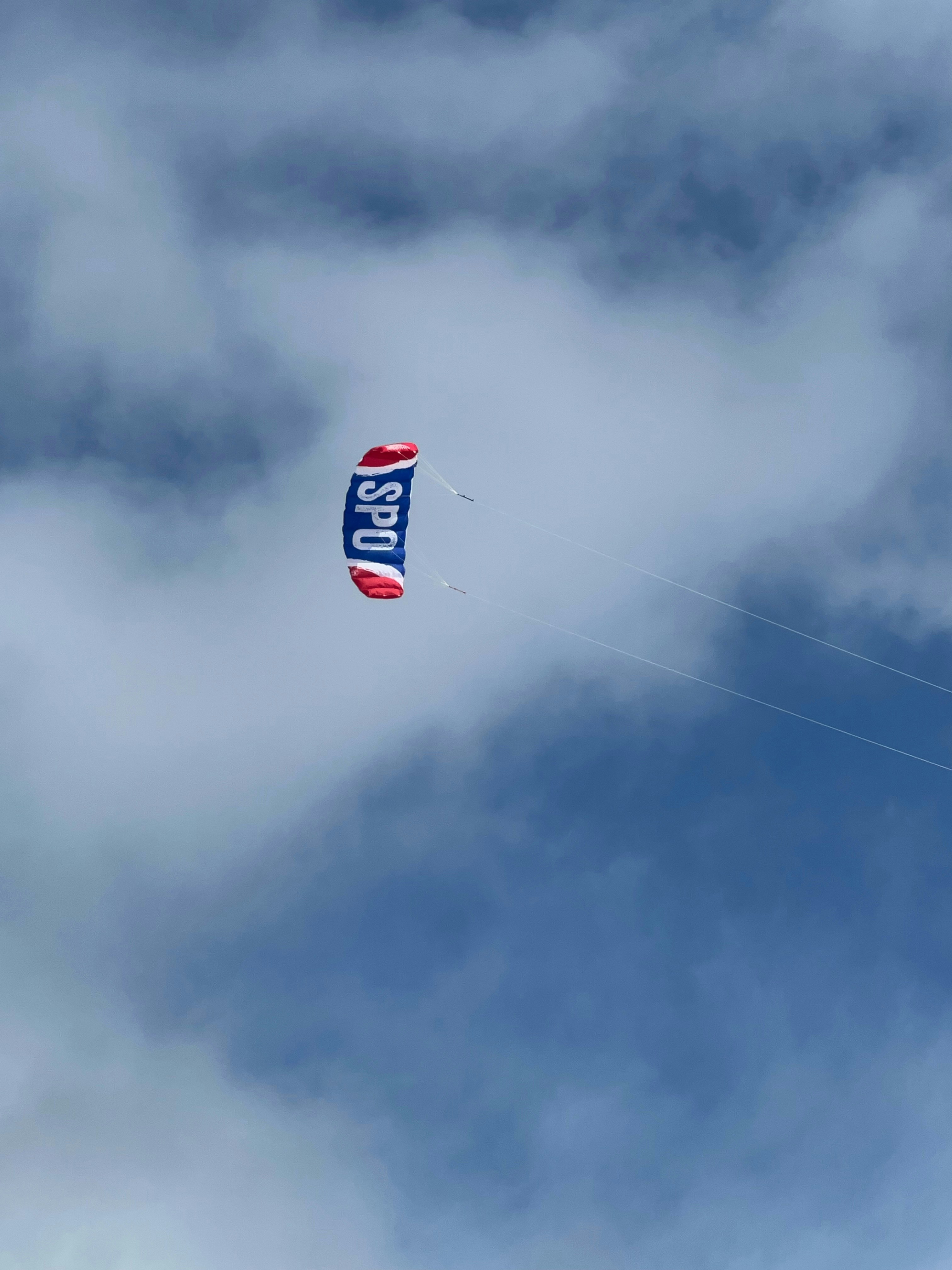 Color-Tethered Glide: A Red-Blue Paraglider Pierces the Cobalt Sky