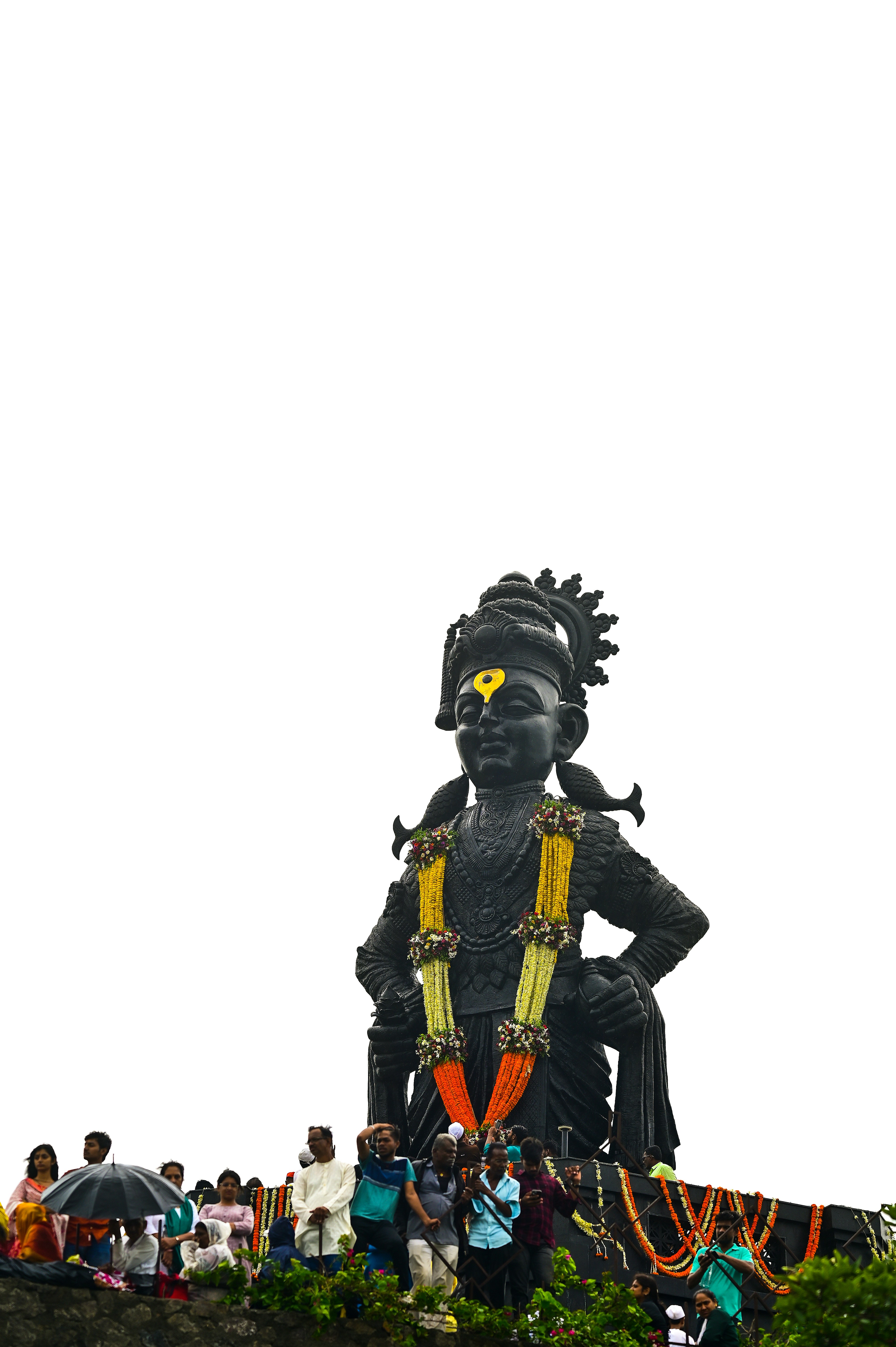 Garlanded Sentinel: A Stone Deity Overlooking a Festival Crowd