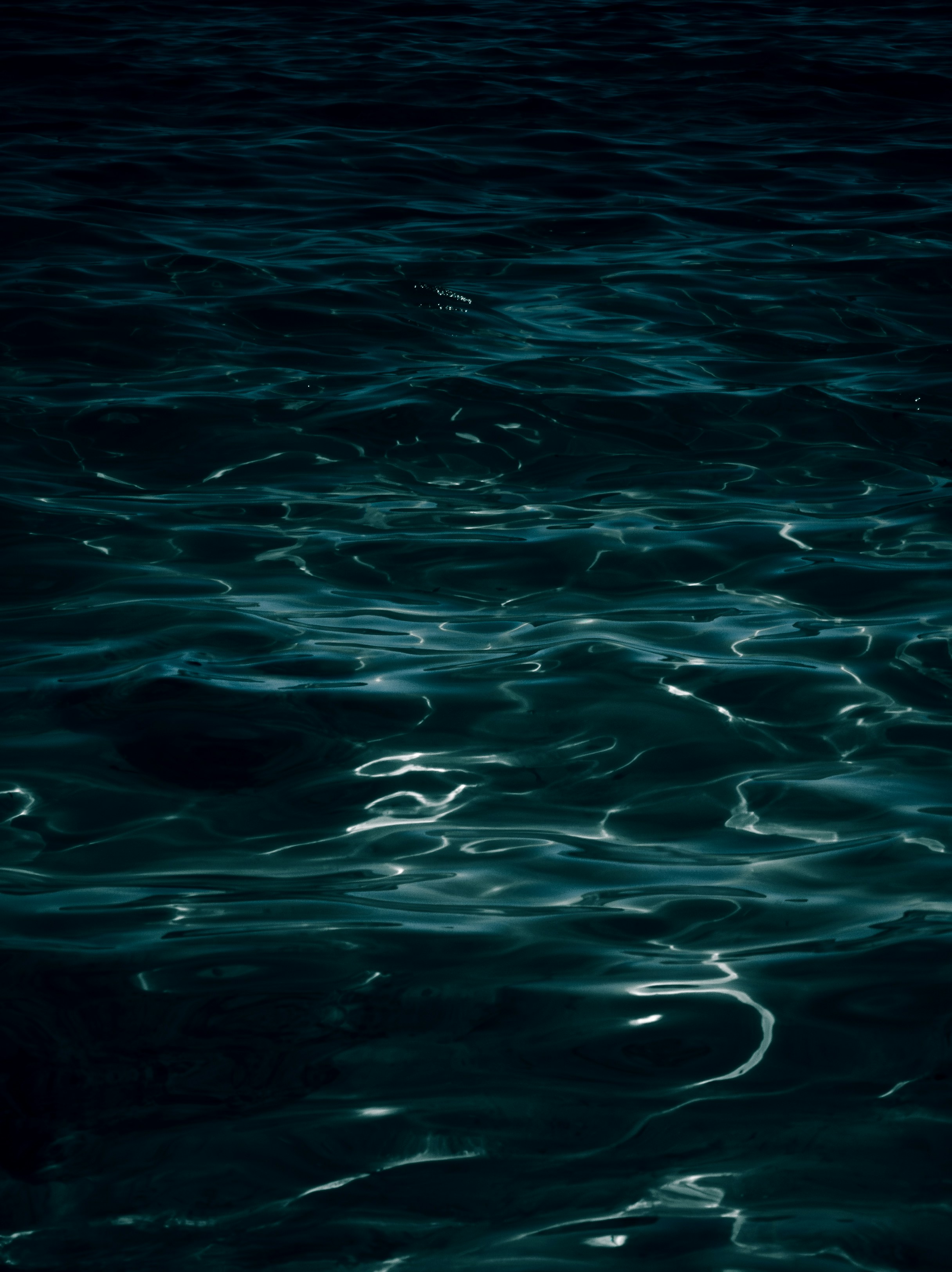 Teal Ripples: Light Trails Across a Quiet Ocean Surface