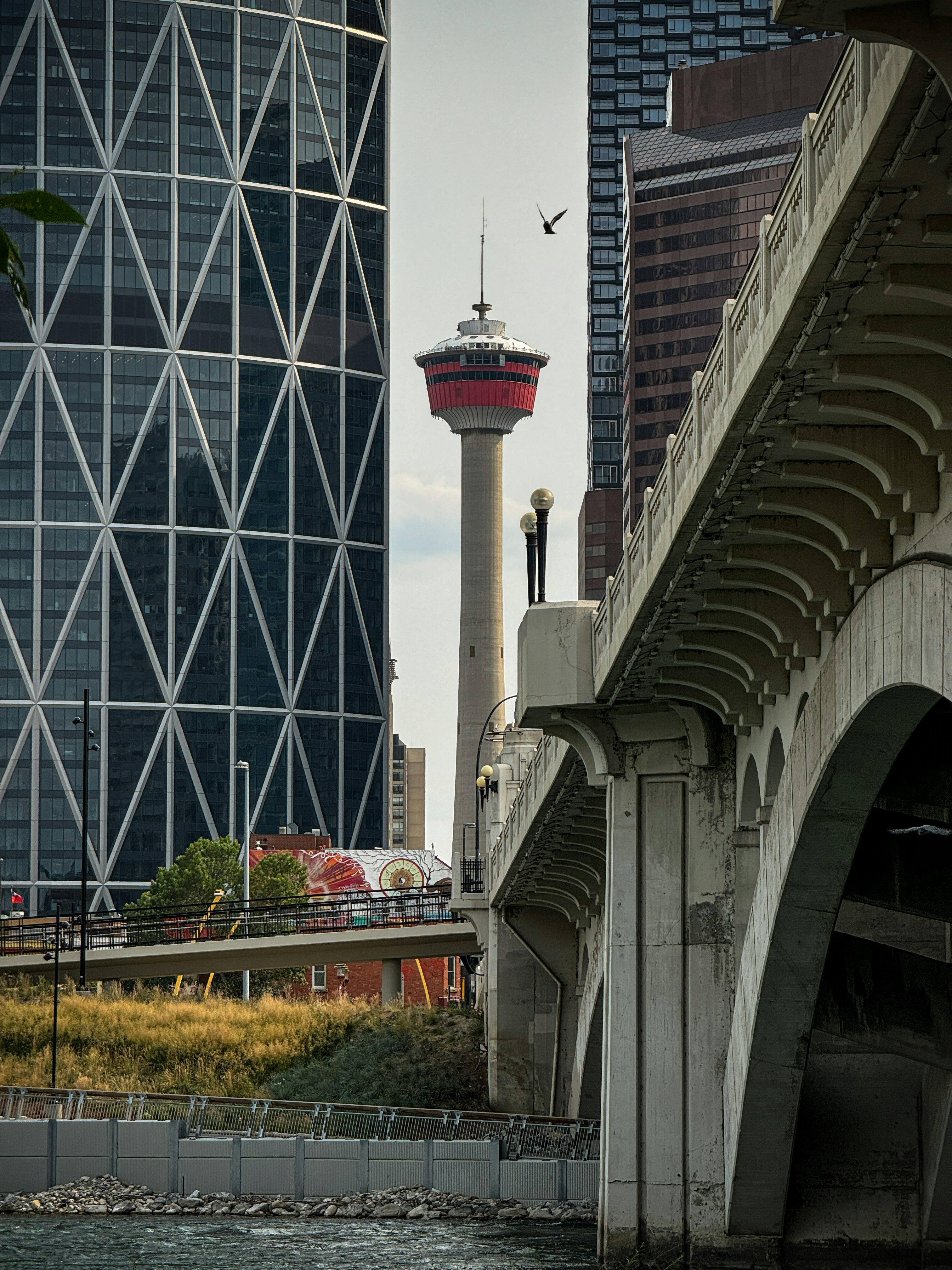Crimson-Top Tower Framed by Glass Skyscrapers and an Arched Bridge